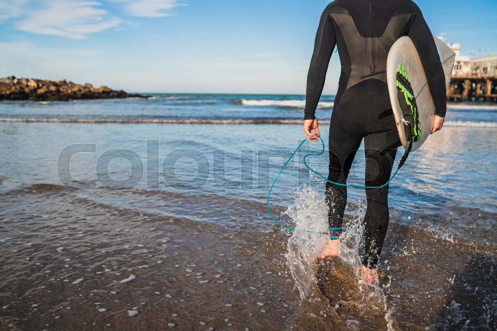 Surfer entering into the water with his surfboard. | Stock image ...