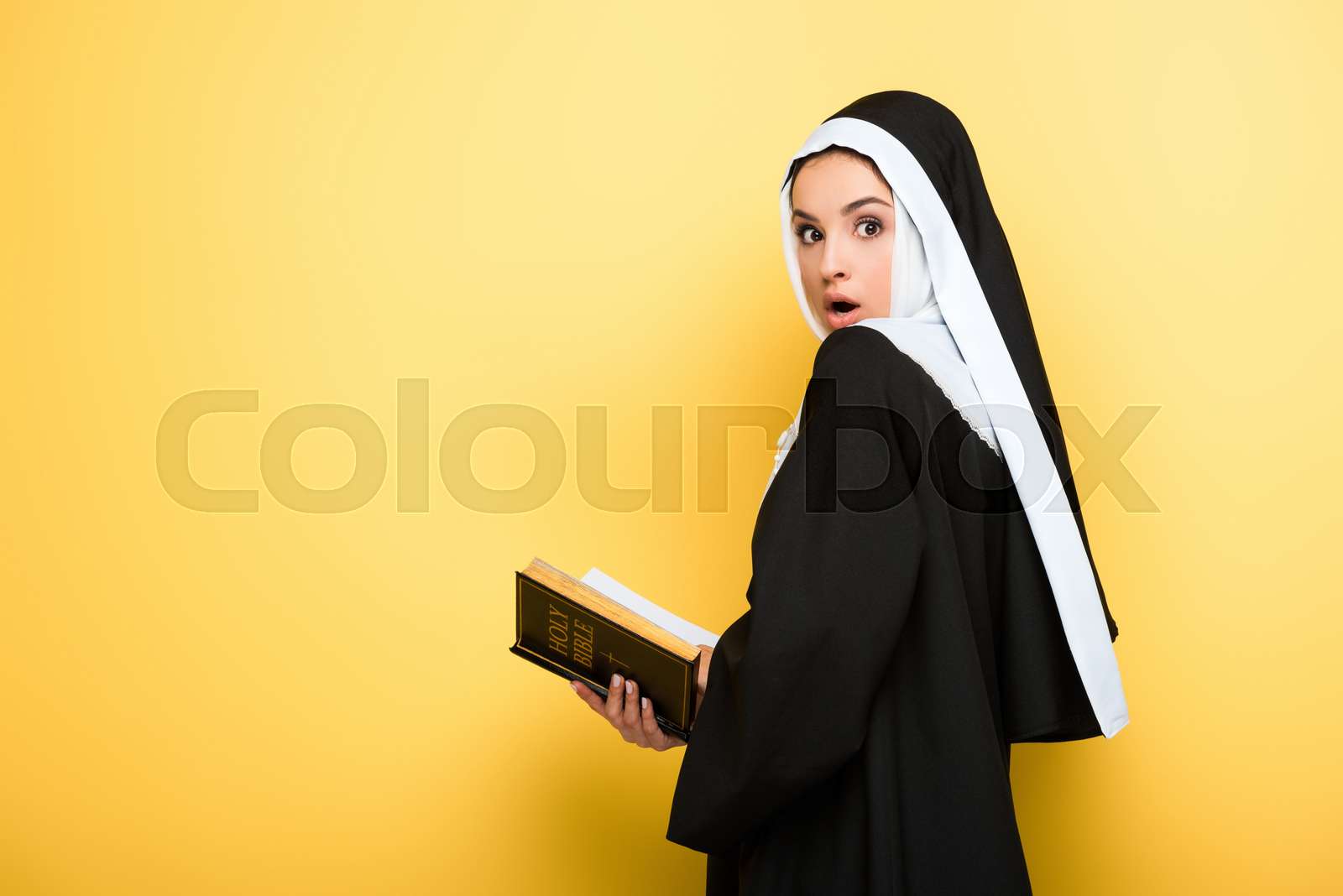 beautiful shocked nun reading holy bible on grey | Stock image | Colourbox