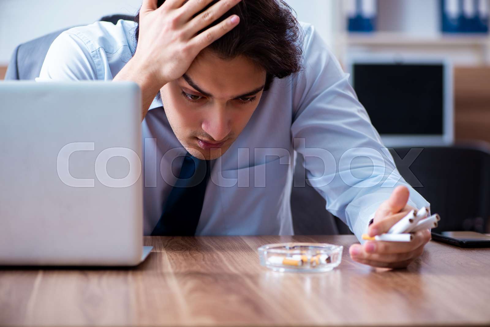 Male employee smoking cigarettes at workplace | Stock image | Colourbox