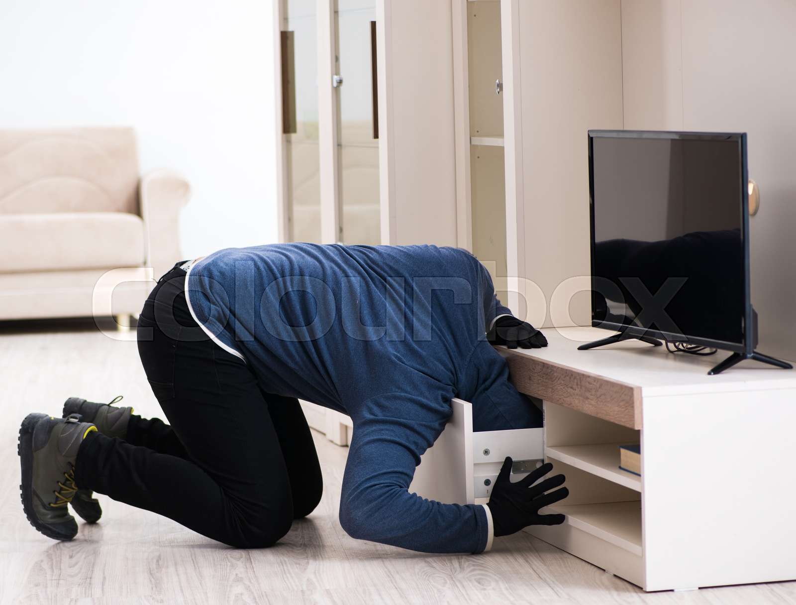 Man burglar stealing tv set from house | Stock image | Colourbox