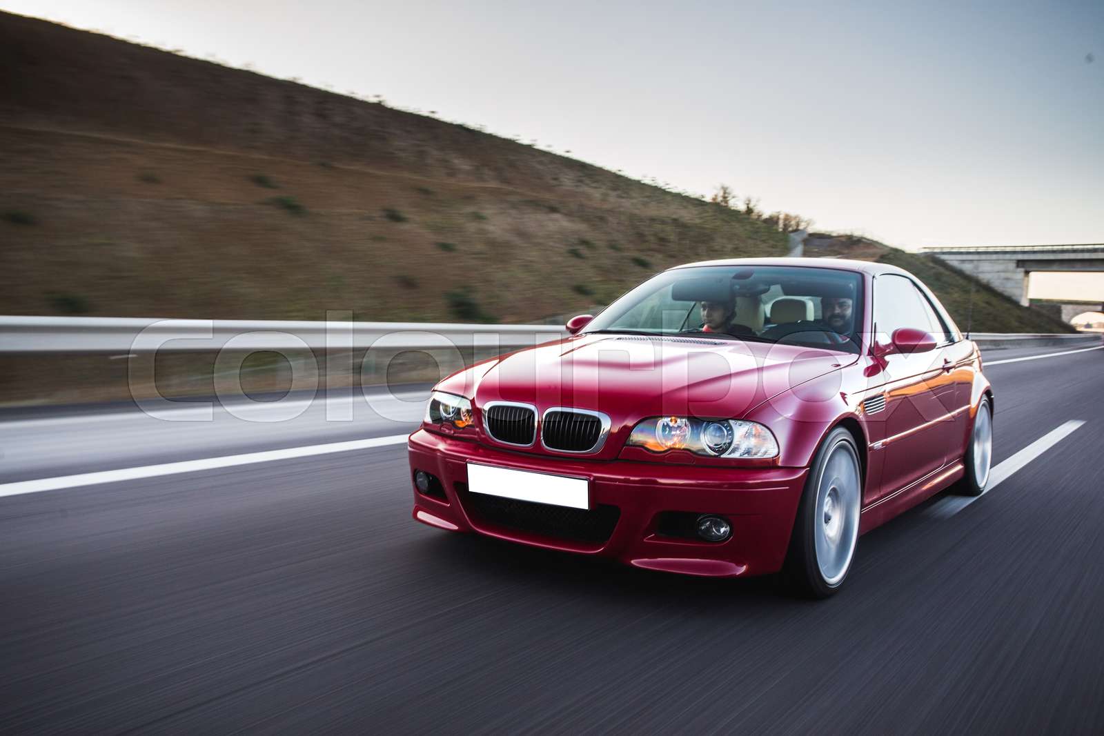Red sedan car driving on the highway under the sunlight, front view ...
