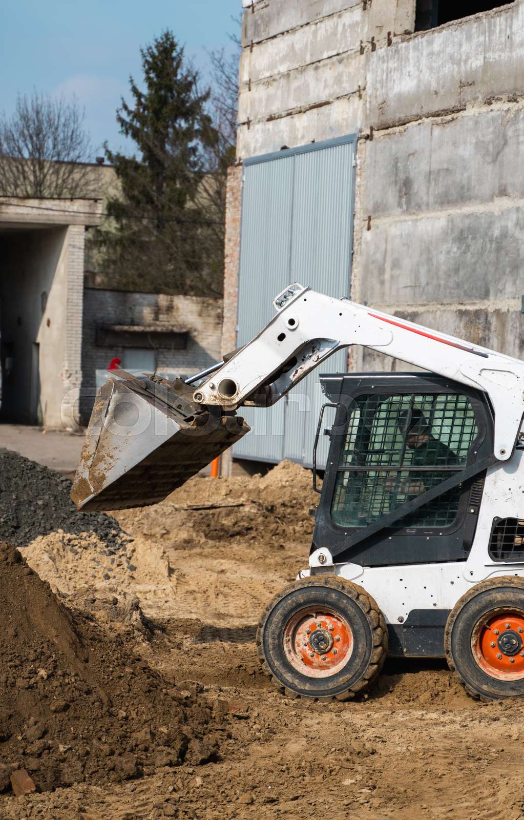 White skid steer loader at a construction site working with a soil ...