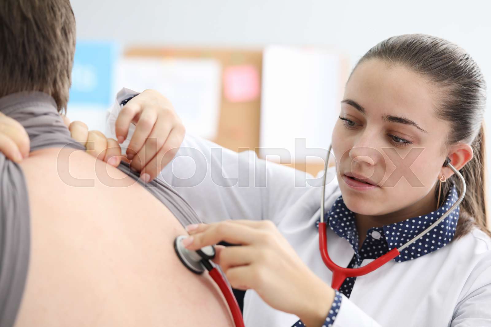 Doctor listening to patient back with stethoscope | Stock image | Colourbox
