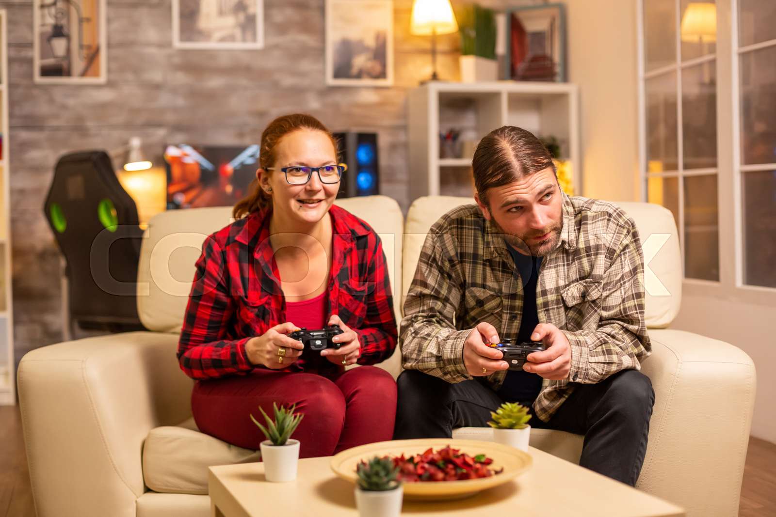 Gamers couple playing video games on the TV with wireless controllers ...