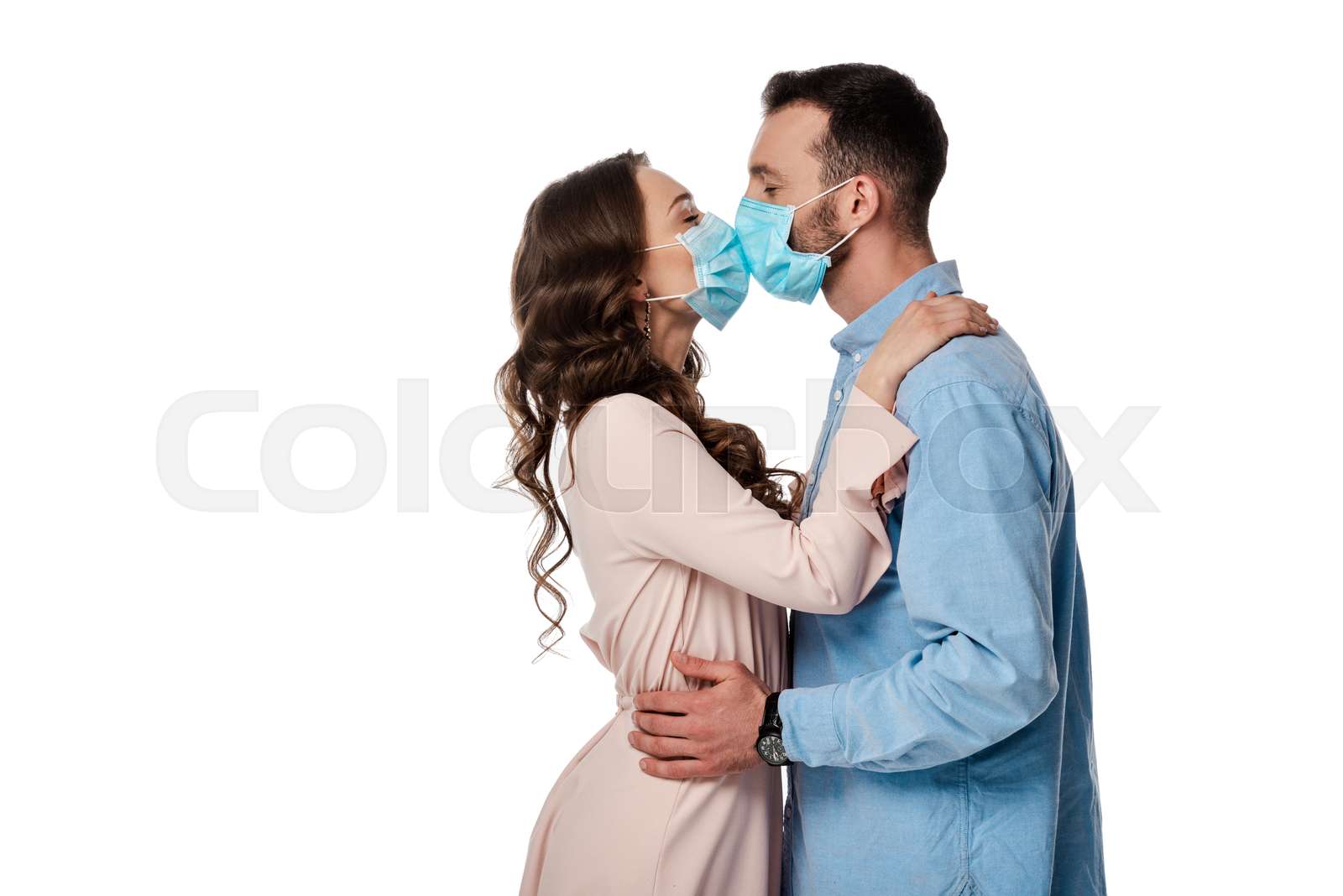 side view of man and woman in medical masks kissing isolated on white ...