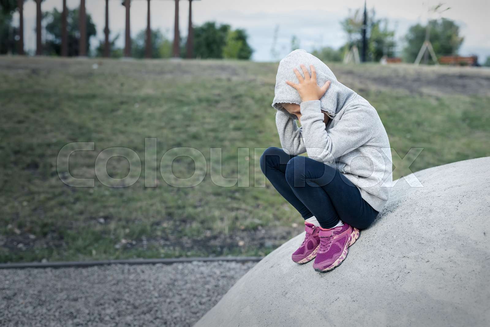 Upset sad depressed little school girl sitting alone at city street ...