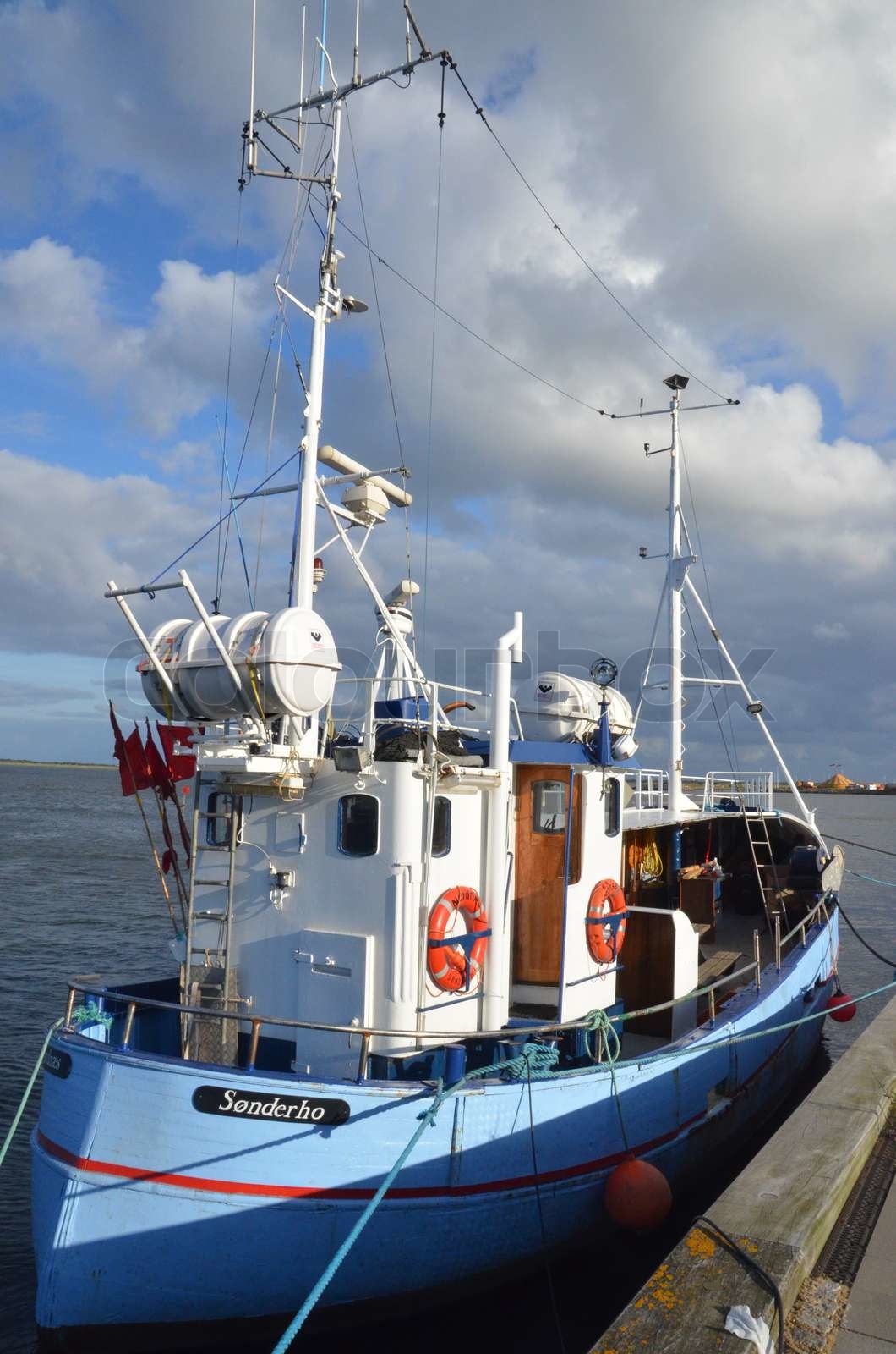 lyseblå fiskekutter med hvid kahyt, rød redningsvest og redningsbåd ...