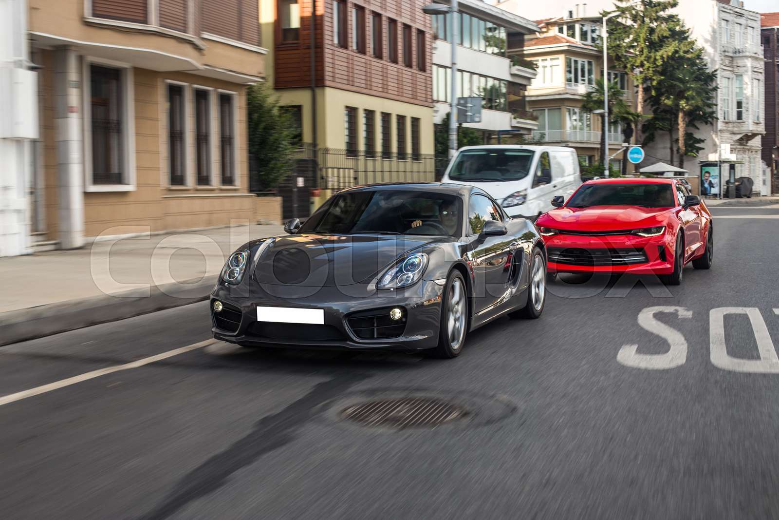 Red and black supercars racing in front of the buildings | Stock image ...