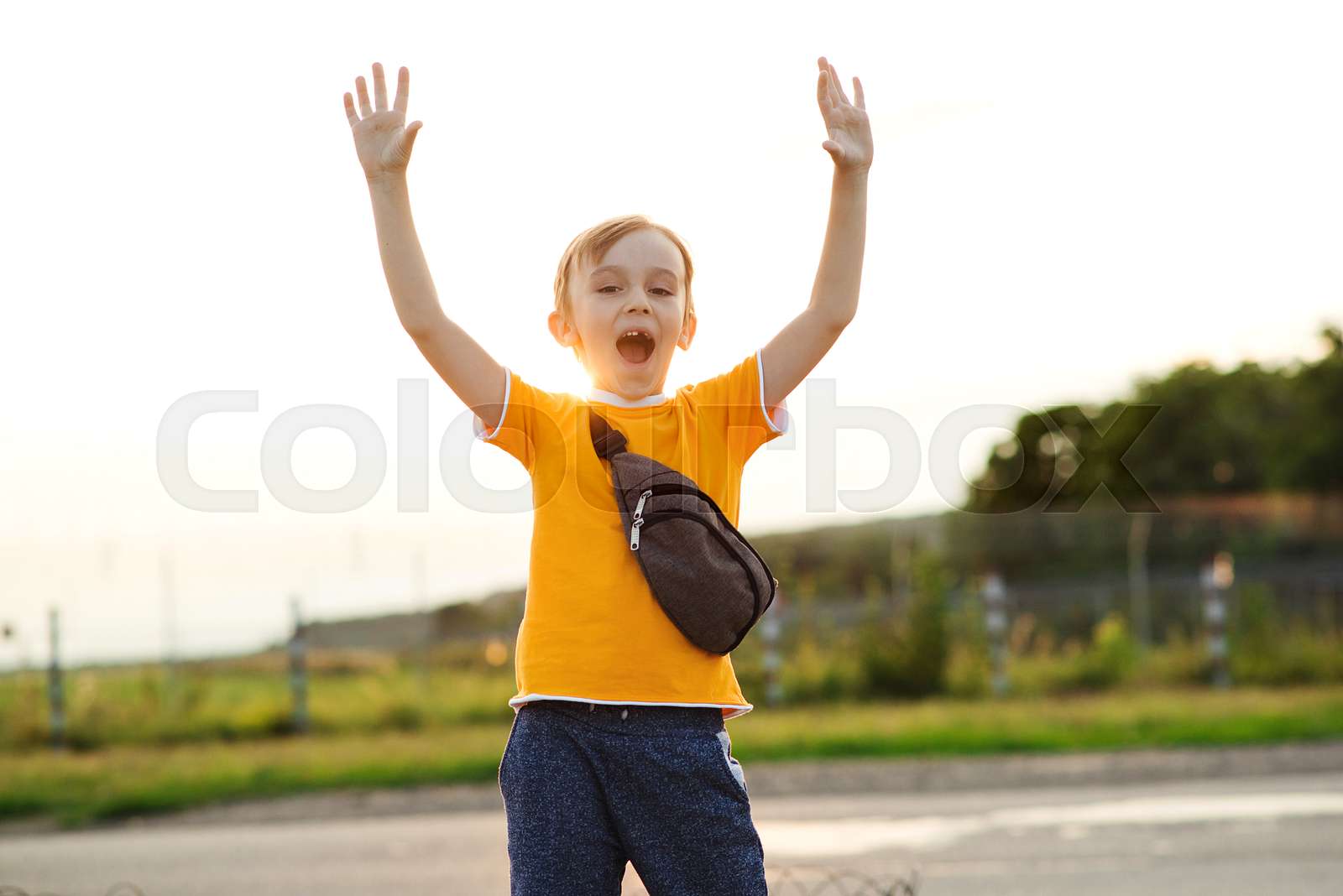 Happy boy jumping outdoors. Boy showing hands up. Happy child having ...