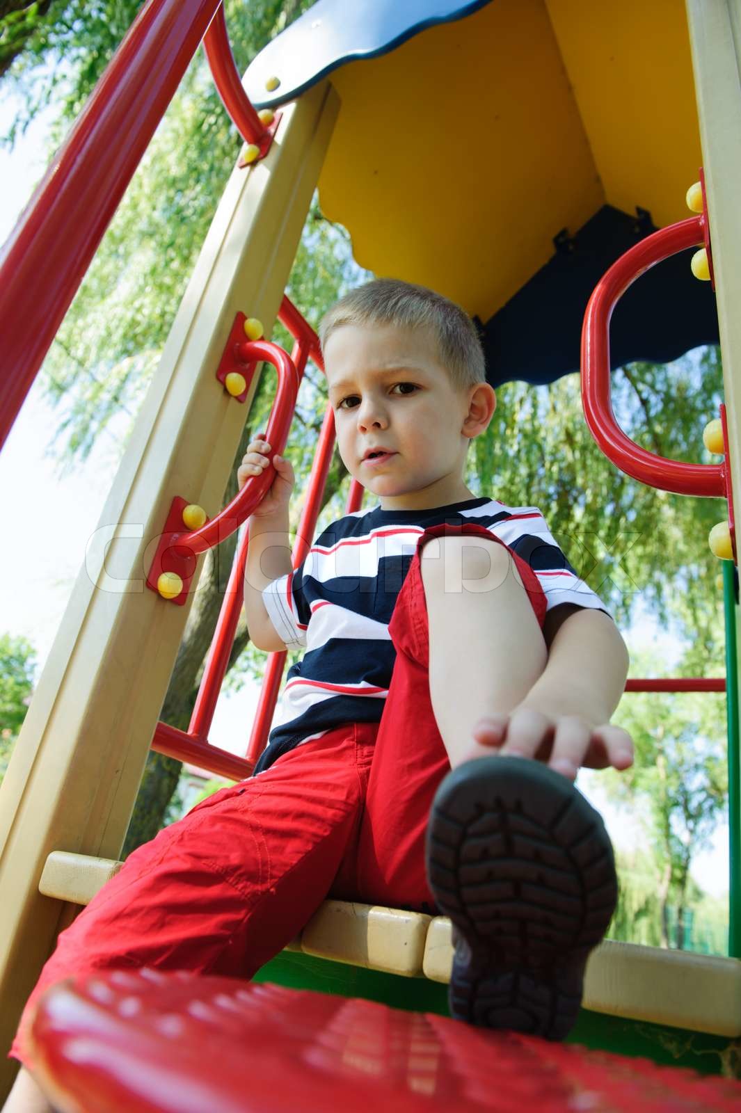 Serious little boy sitting at playground | Stock image | Colourbox
