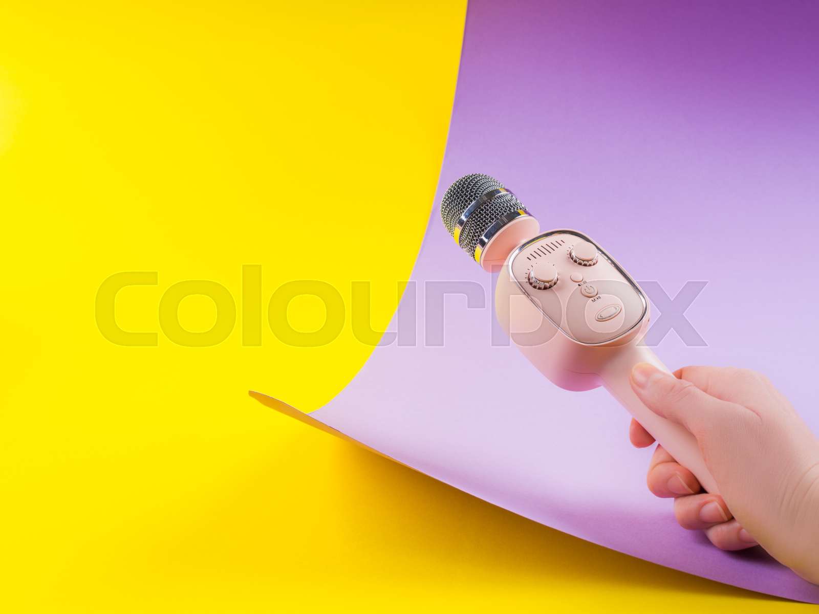 Pastel pink microphone in female hand | Stock image | Colourbox