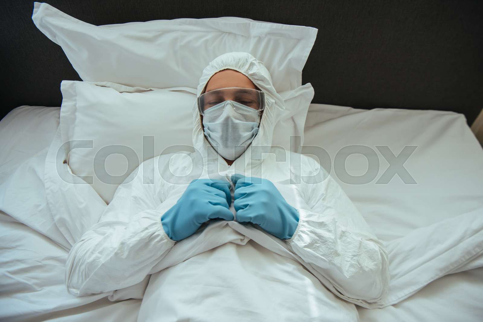 man in hazmat suit, medical mask and goggles sleeping in bedroom ...