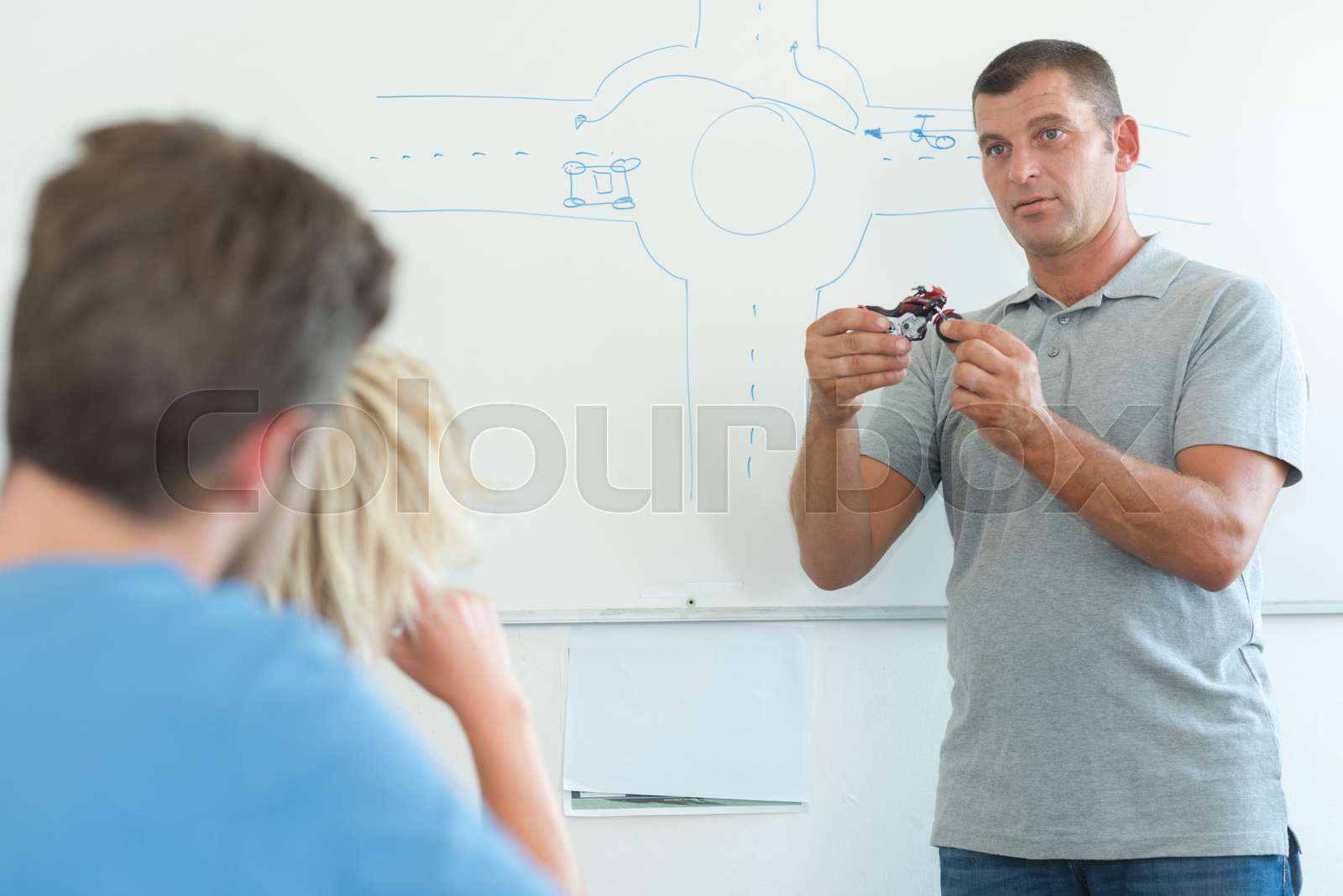 driving school teacher showing a motorbike model | Stock image | Colourbox