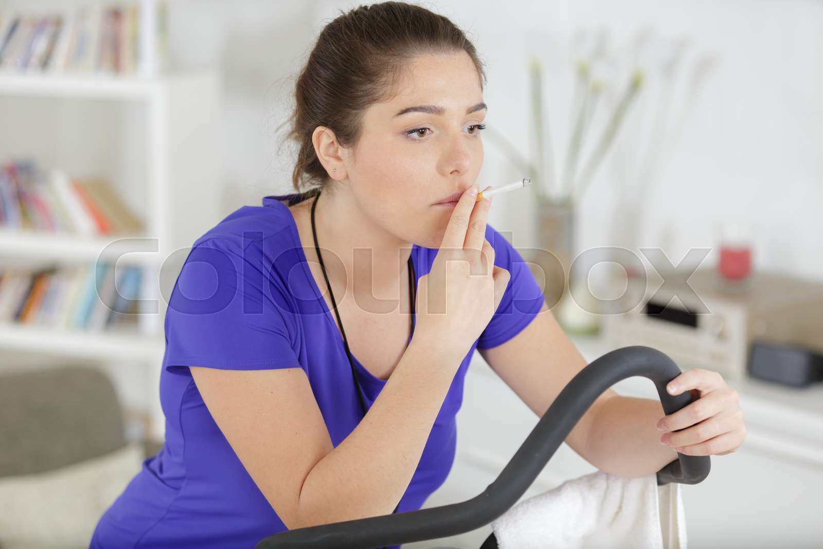 young woman smoking a cigarette while exercising | Stock image | Colourbox