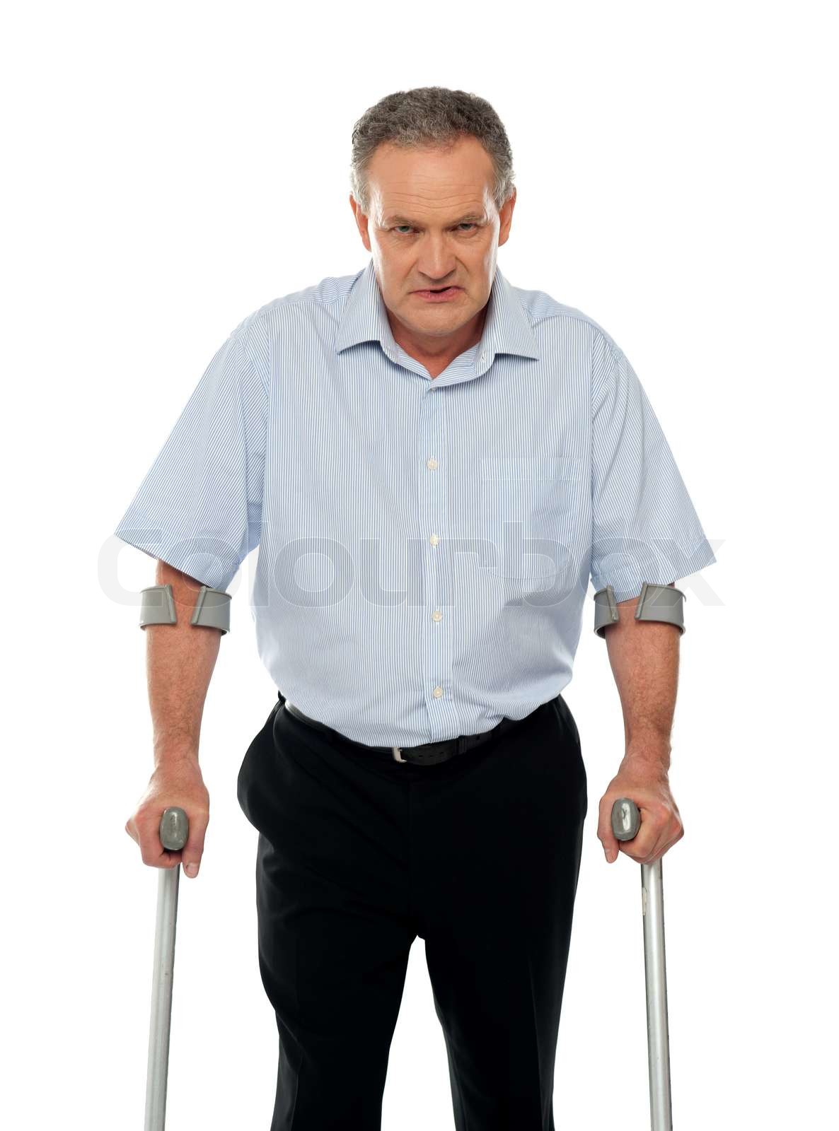 Angry aged man with crutches looking at you | Stock image | Colourbox