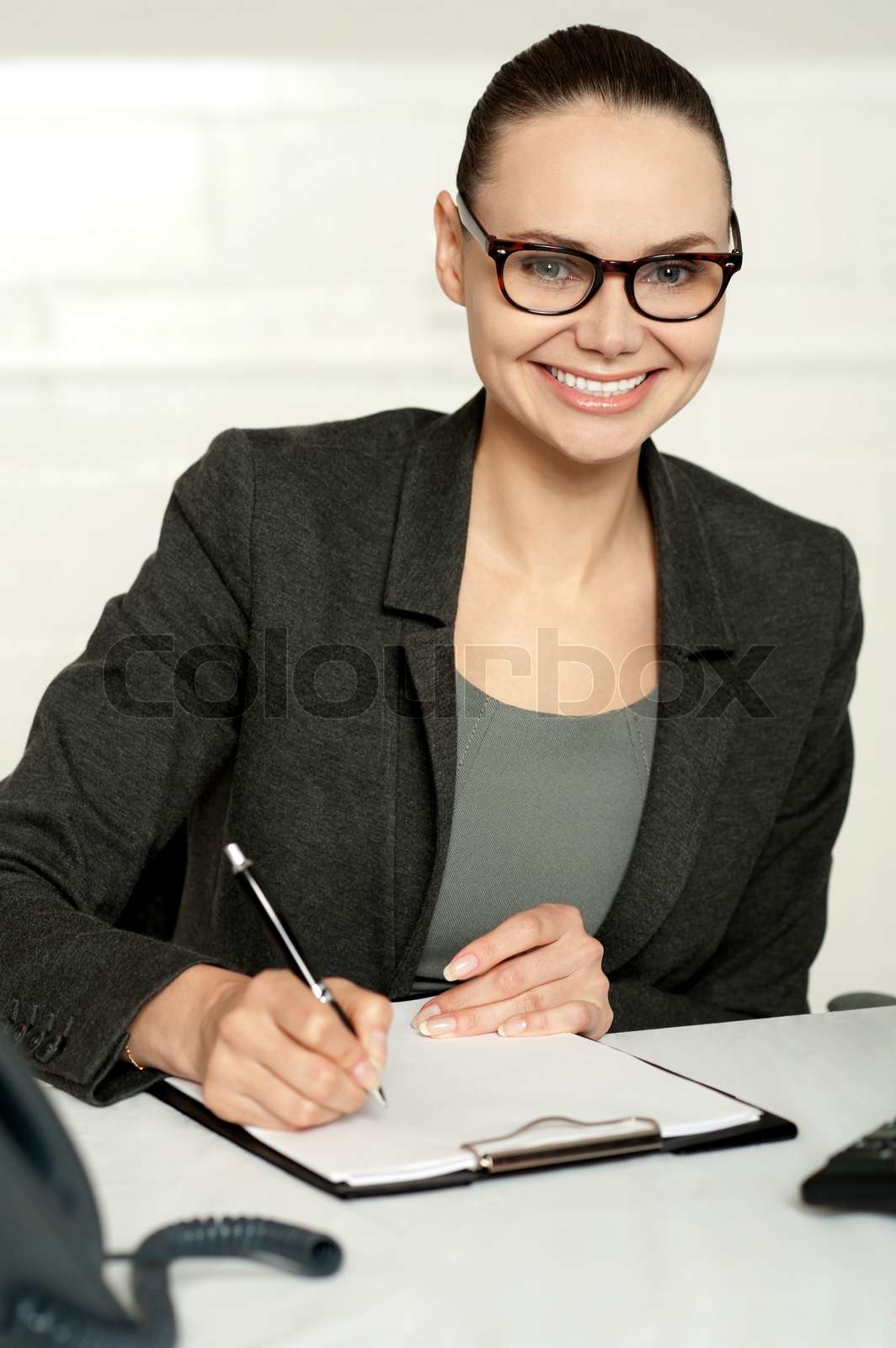 Secretary writing key business notes on clipboard | Stock image | Colourbox