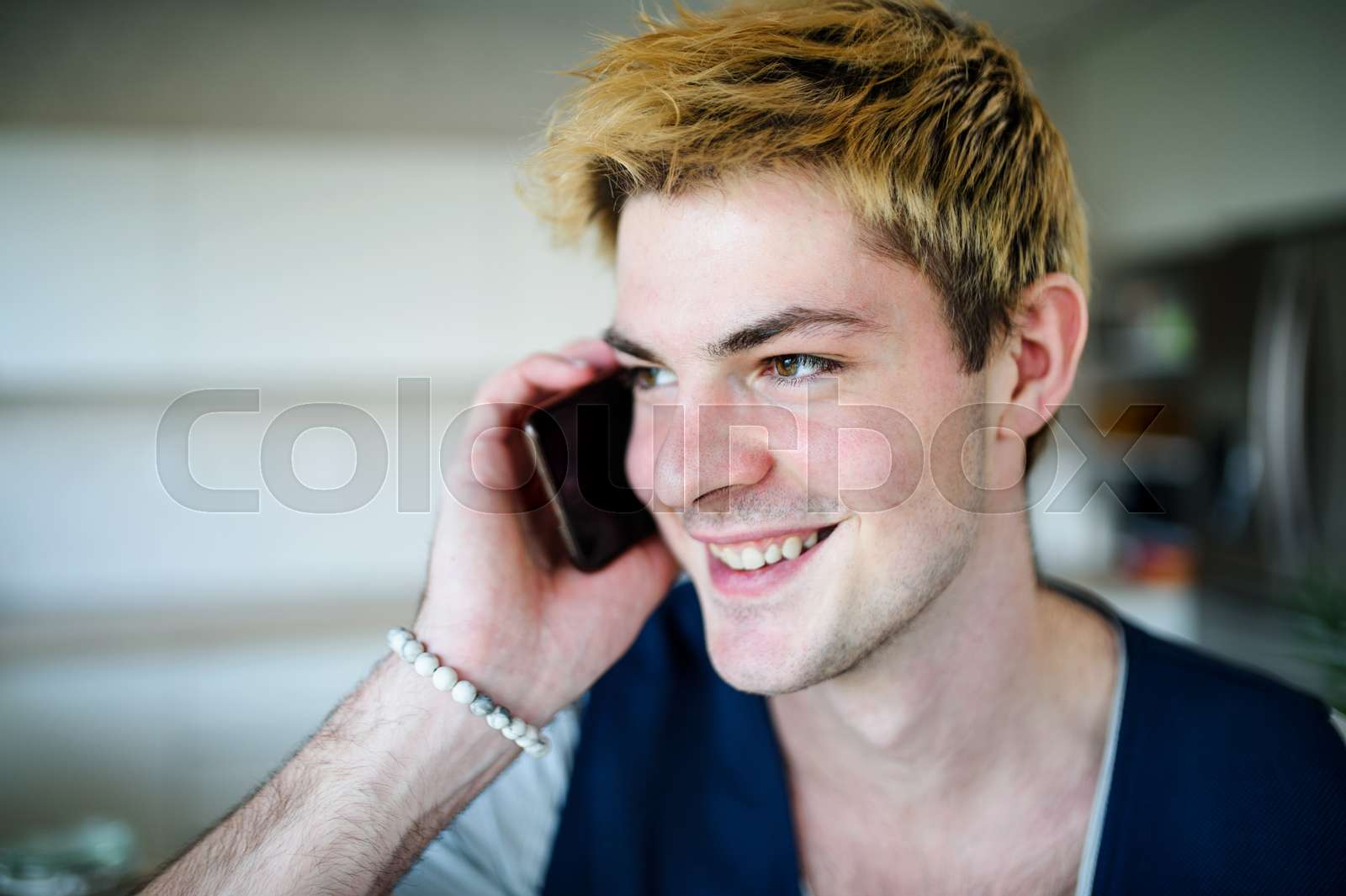 Close-up of young man with smartphone indoors at home, making phone ...