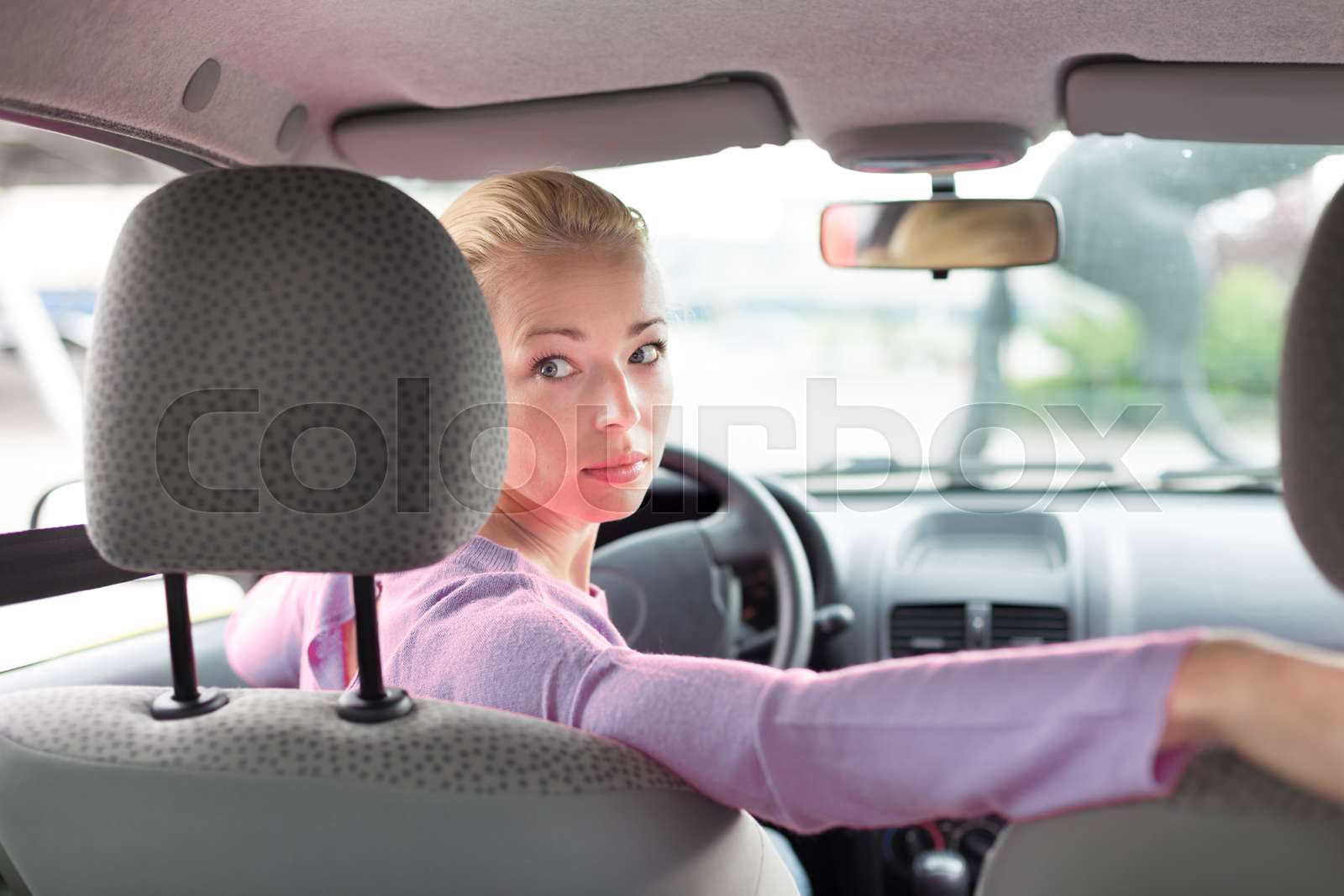 Female driver looking back while reversing in car. | Stock image ...