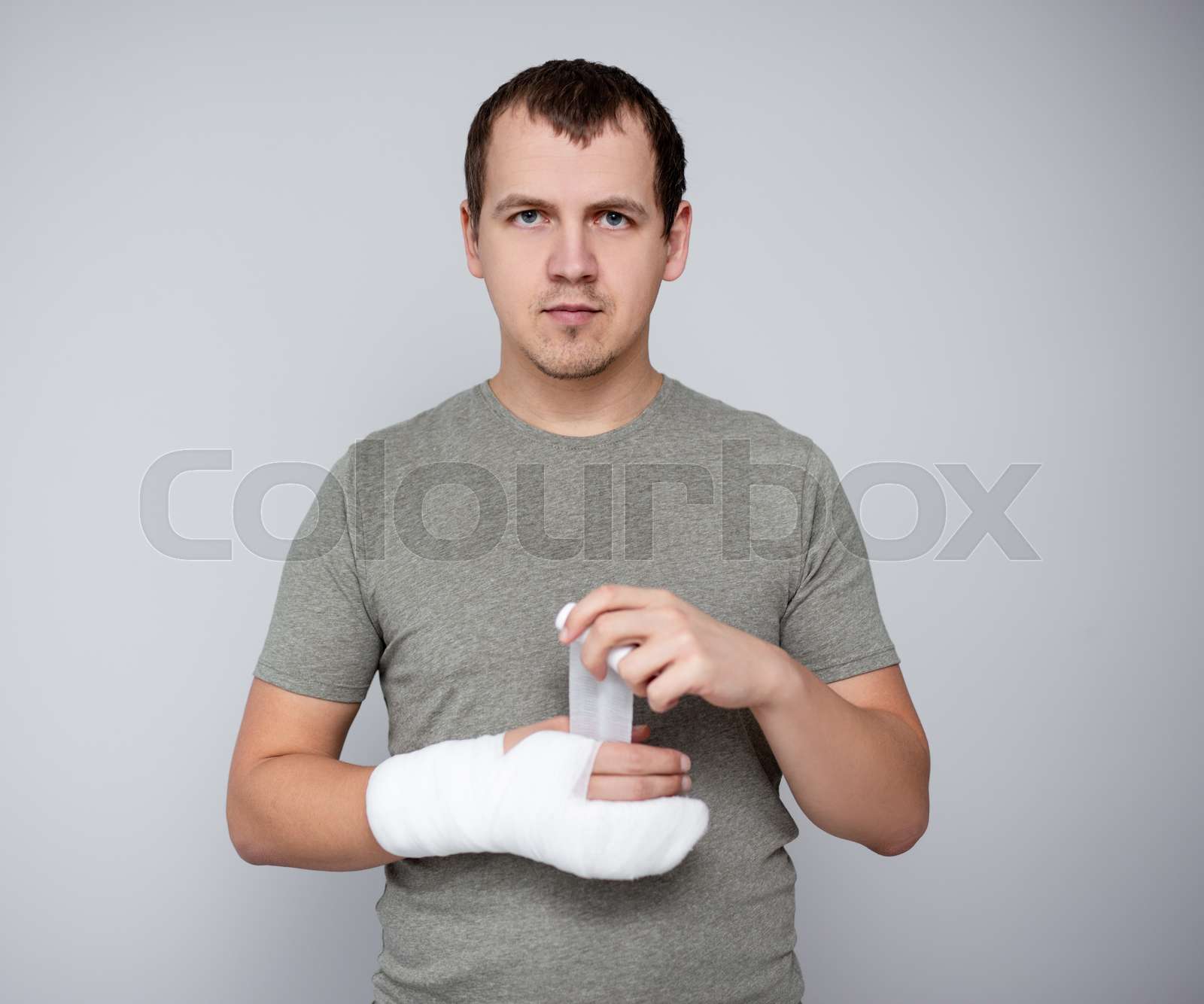 fracture and first aid concept - portrait of young man bandaging his ...