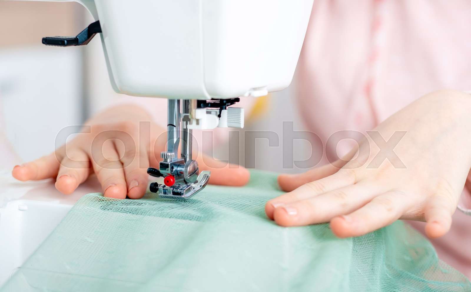 Closeup portrait of a girl using a sewing machine | Stock image | Colourbox