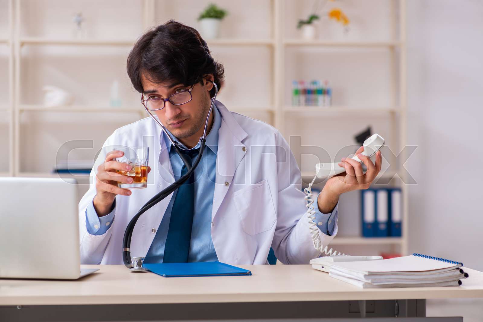 Young male doctor drinking in the office | Stock image | Colourbox