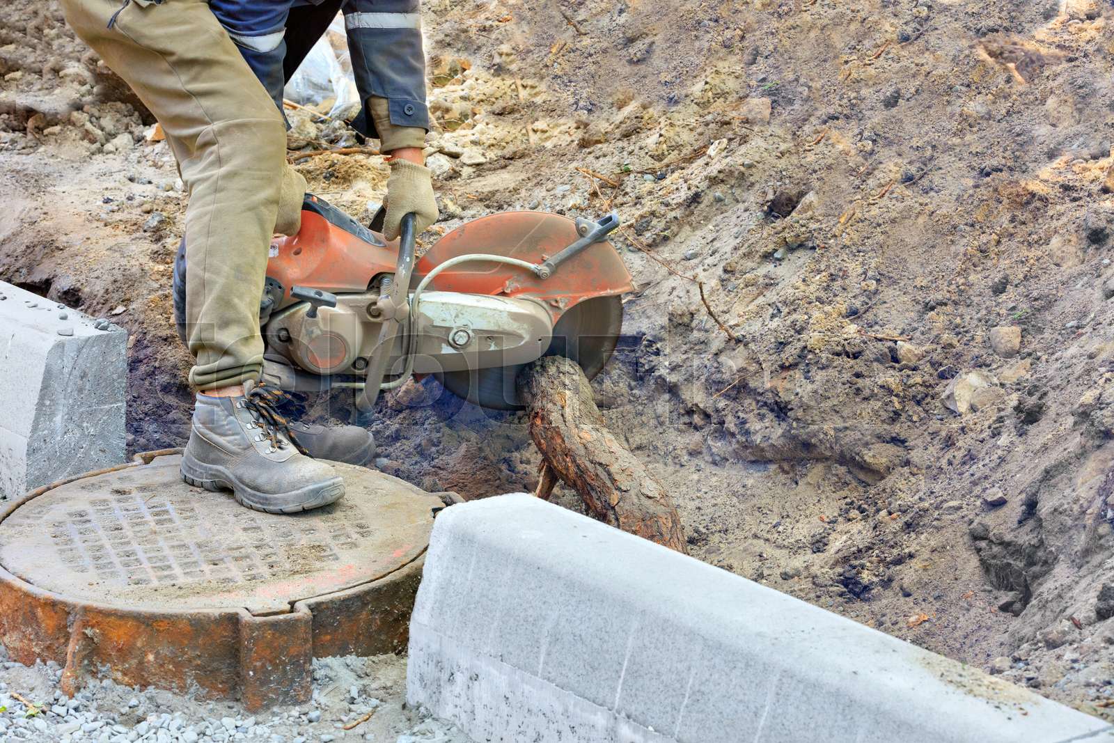 A worker using a portable gasoline saw clears the site and cuts the ...