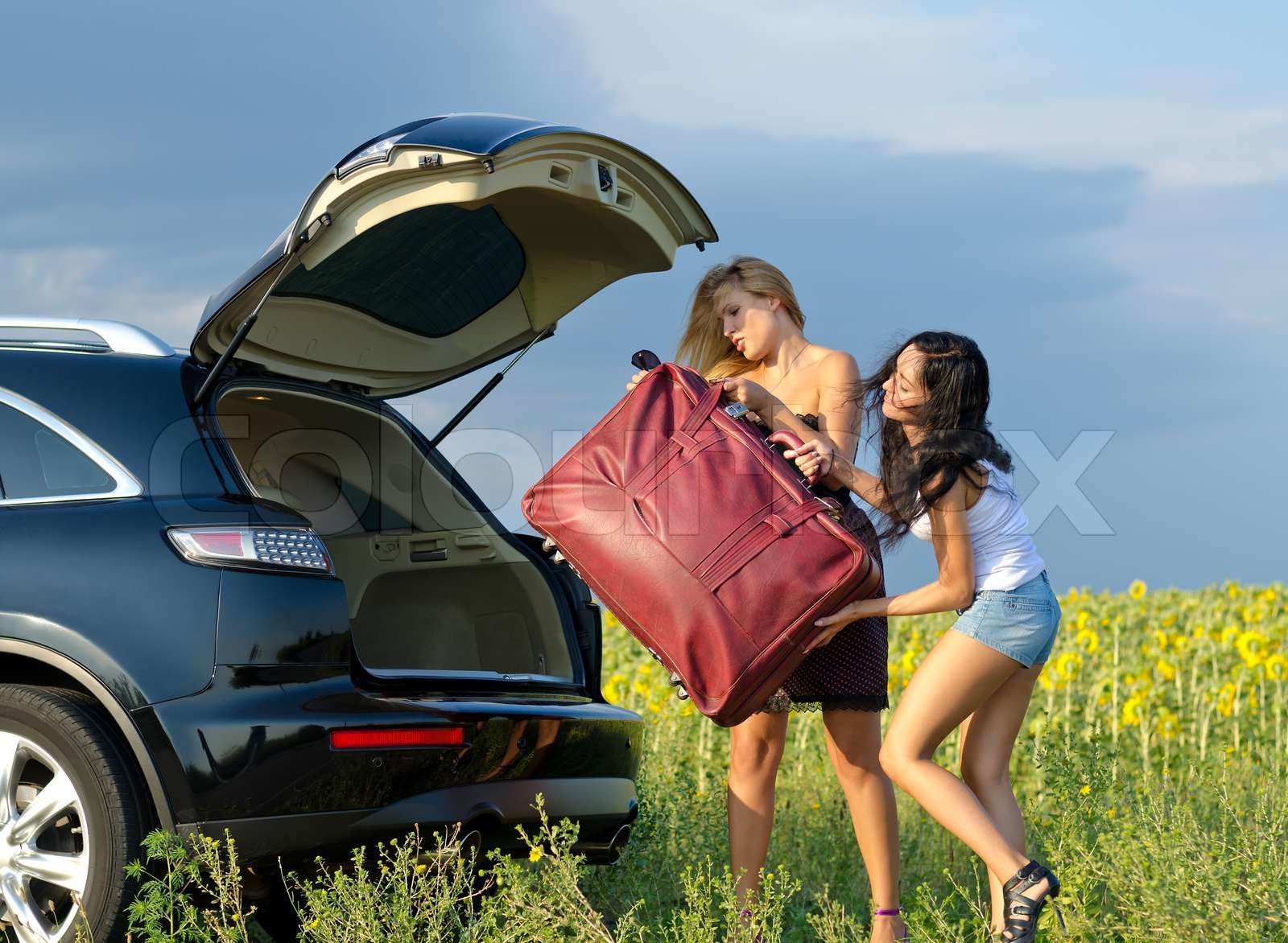 Women loading a heavy bag into car | Stock image | Colourbox