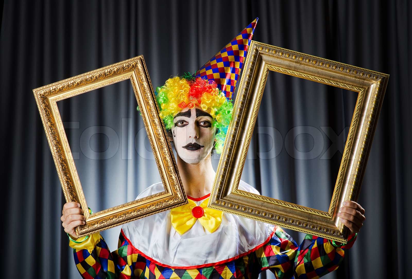 Clown with picture frames in studio | Stock image | Colourbox