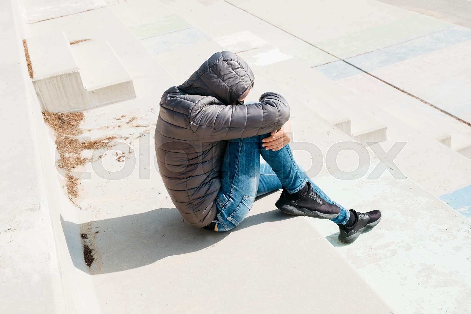 man curled up sitting on an outdoor stairway | Stock image | Colourbox