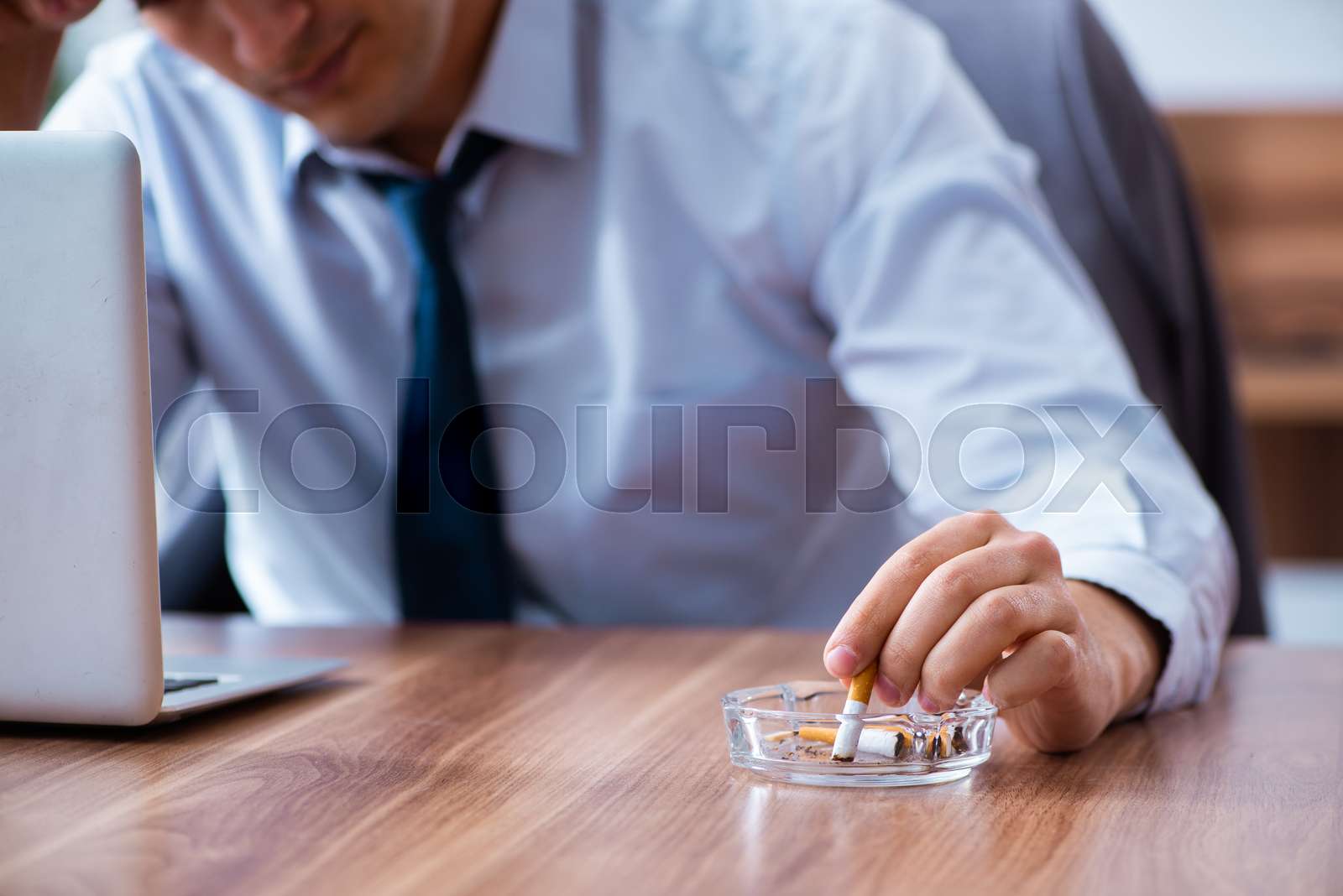 Male employee smoking cigarettes at workplace | Stock image | Colourbox