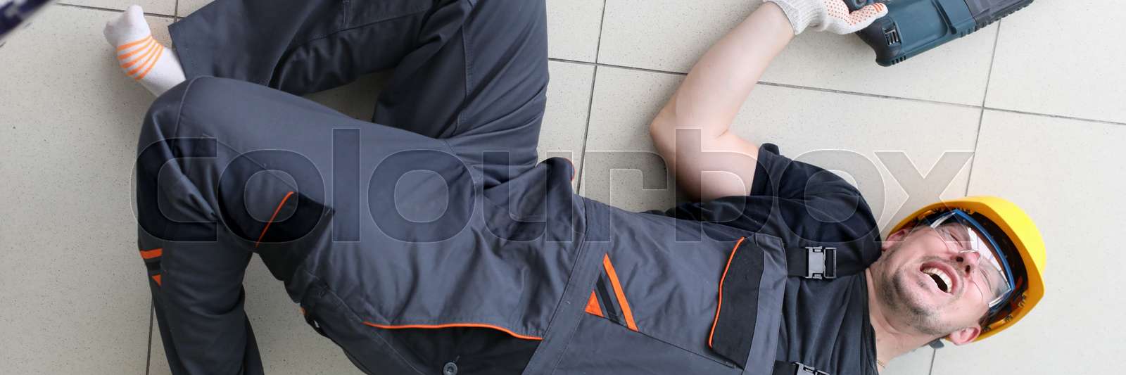 Severe pain in back builder, man lies on floor. | Stock image | Colourbox