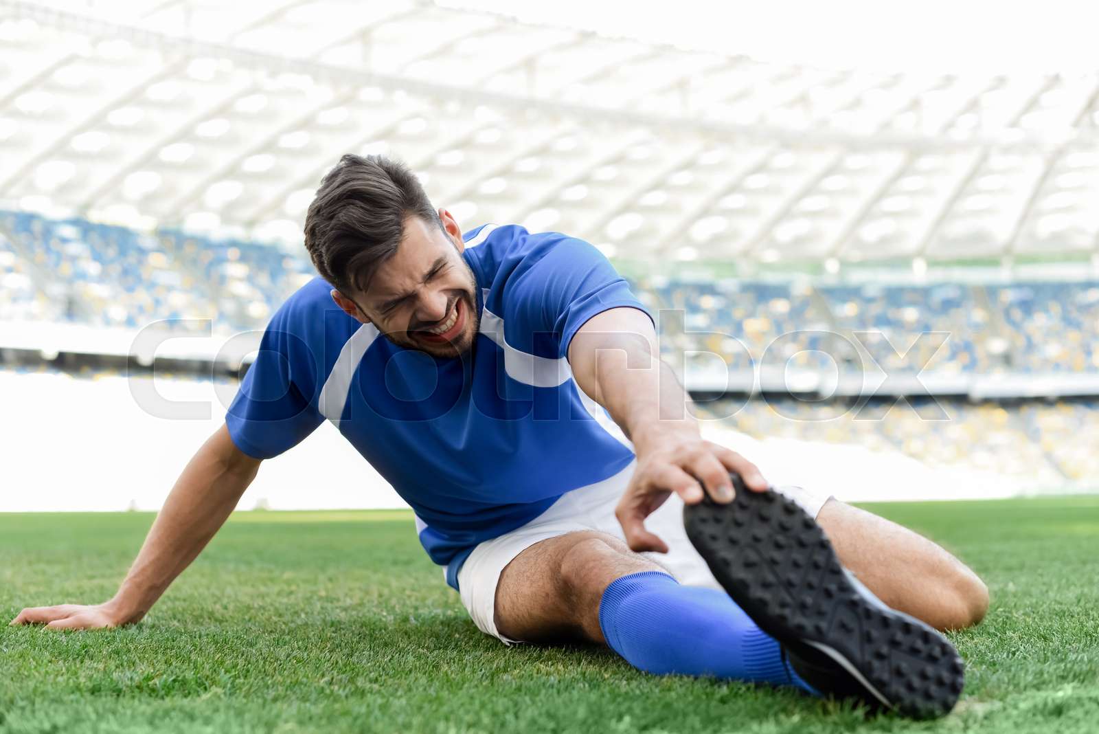 professional soccer player in blue and white uniform stretching on ...