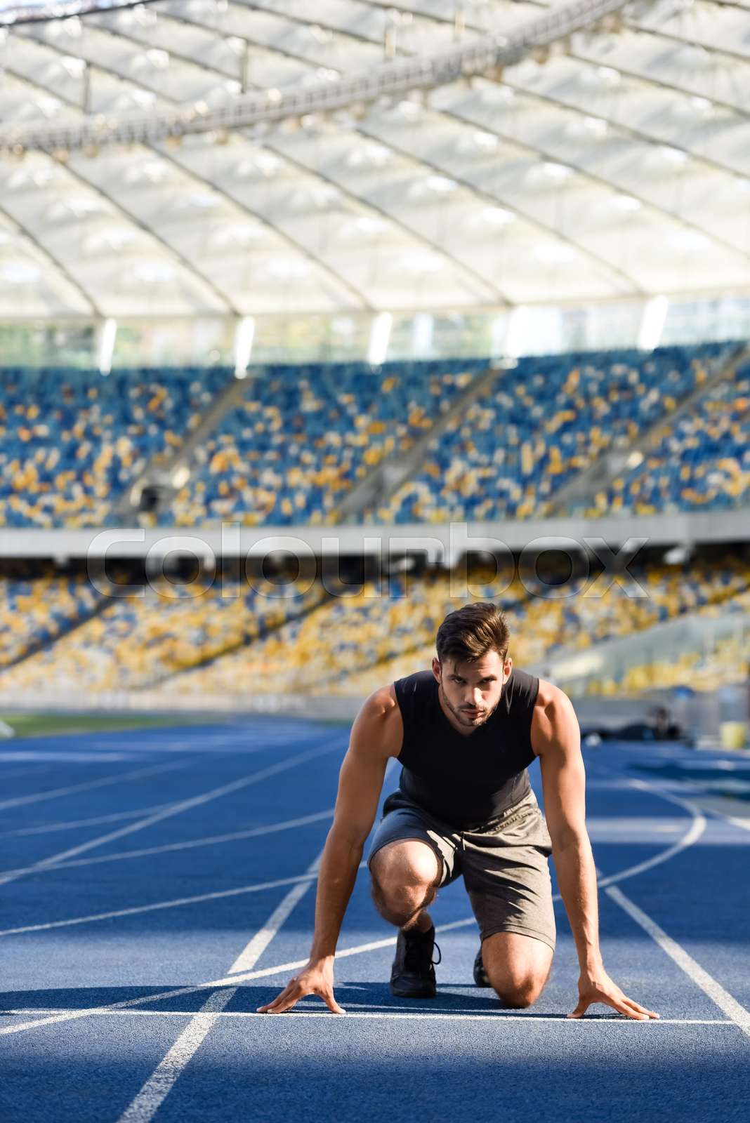 handsome runner in start position on running track at stadium | Stock ...