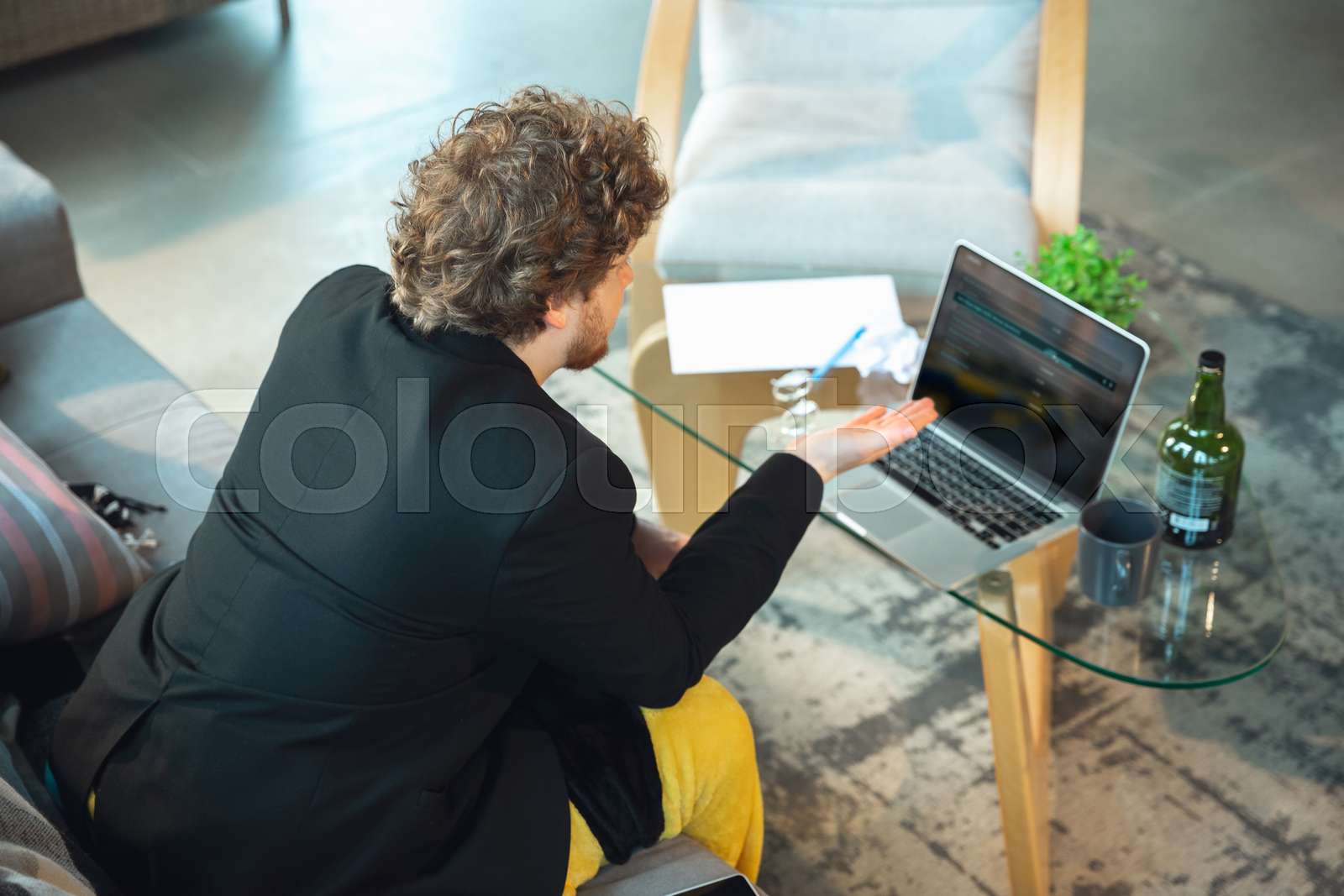 Young man in pajama and jacket working on a computer, laptop. Remote ...