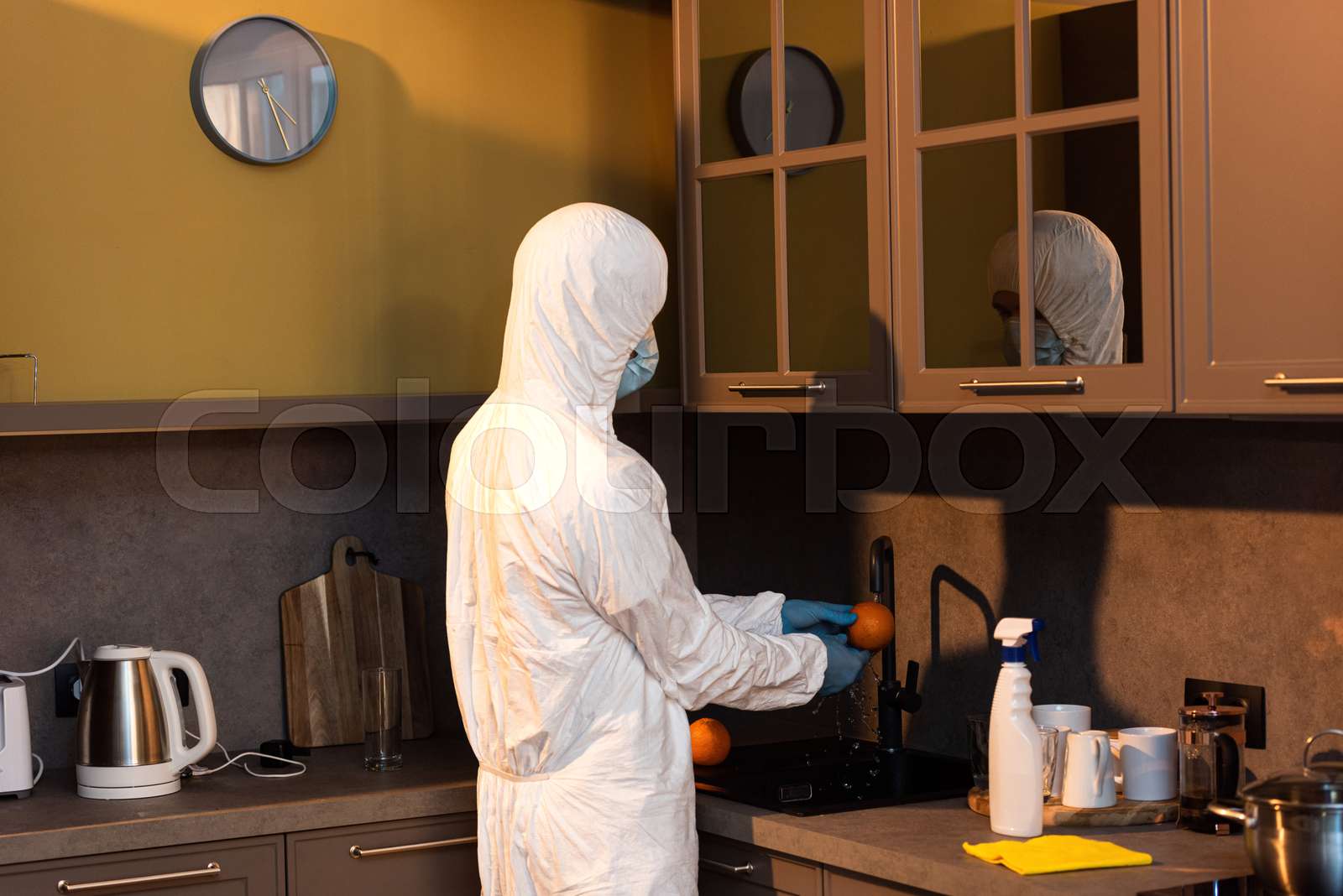 Side view of man in hazmat suit, latex gloves and medical mask washing ...