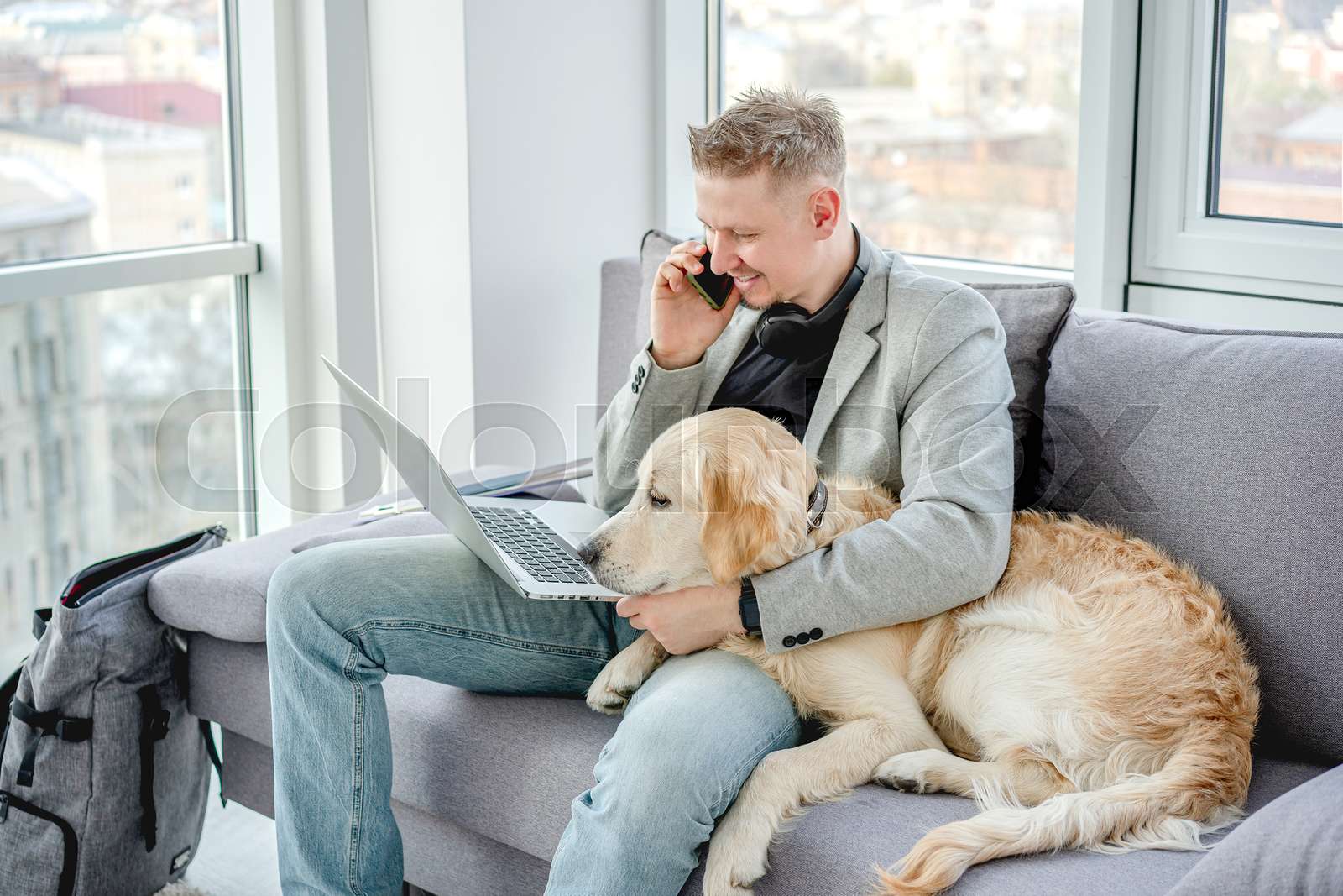 Handsome man cuddling dog while working | Stock image | Colourbox