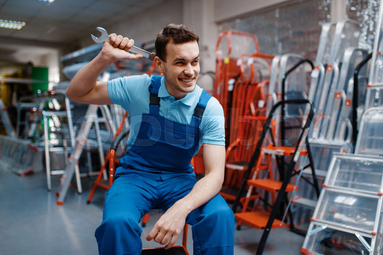 Smiling male worker holds wrench in tool store | Stock image | Colourbox
