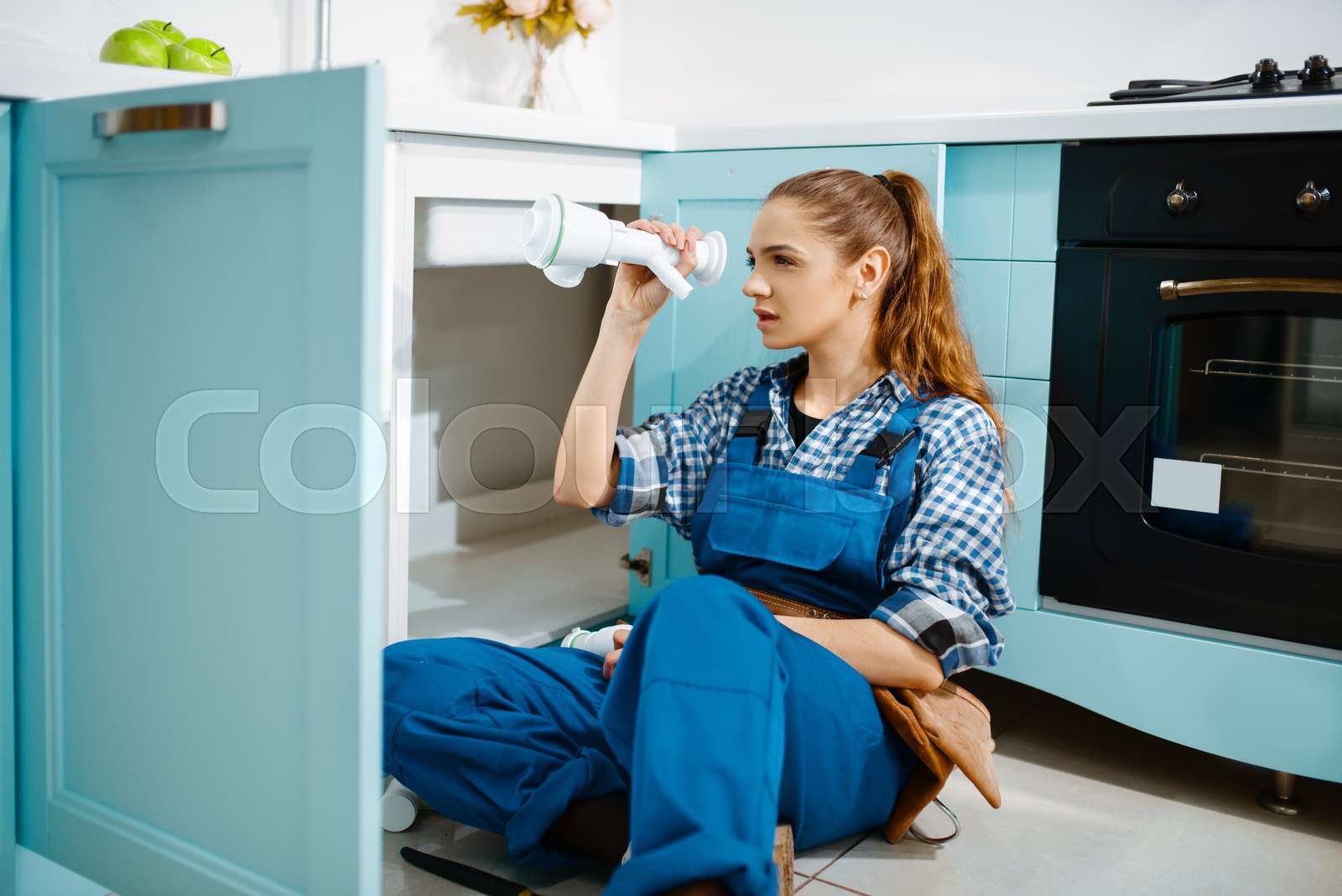 Female plumber fixing problem with drain pipe | Stock image | Colourbox