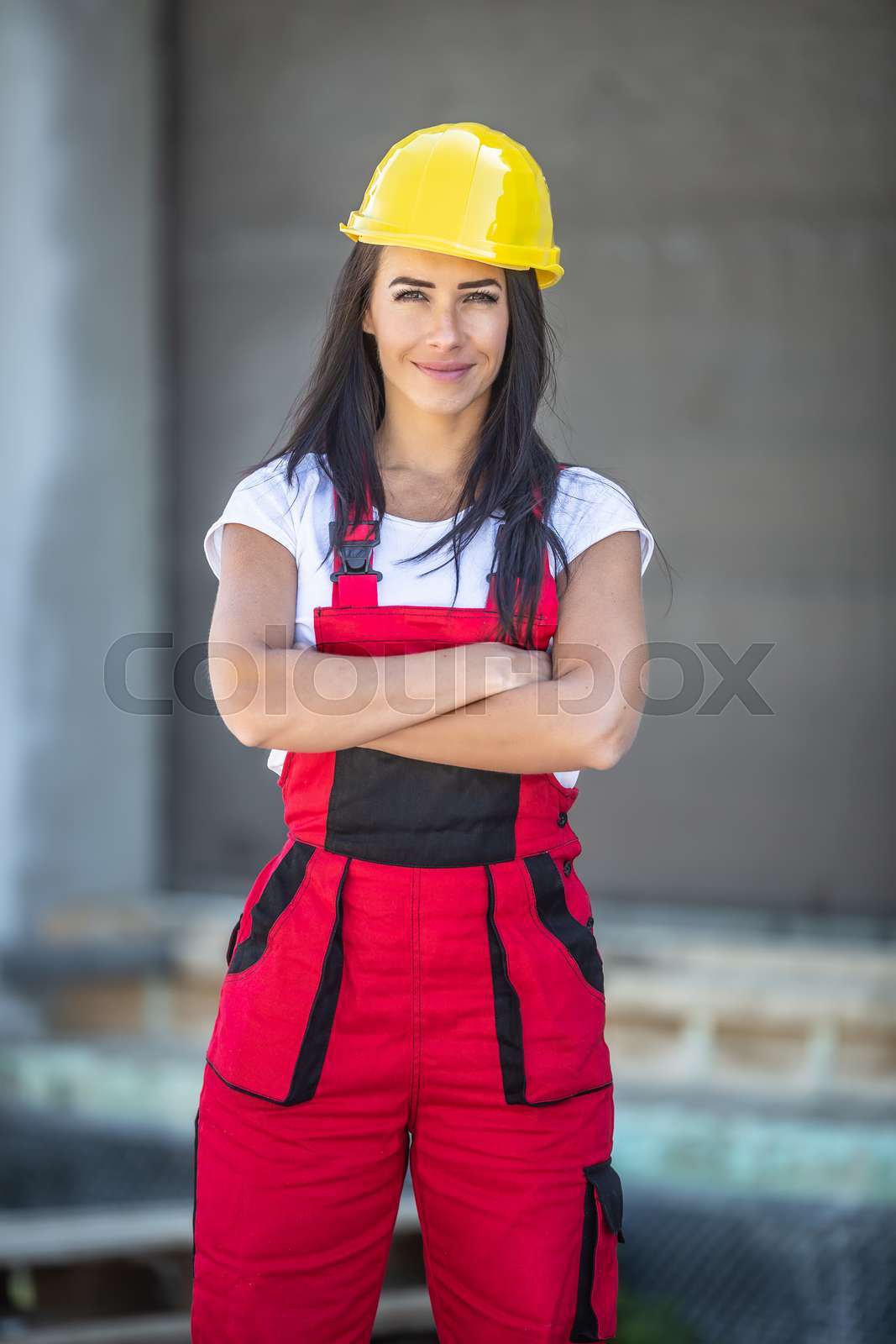 Female builder stands with arms crossed on a construction site dressed ...