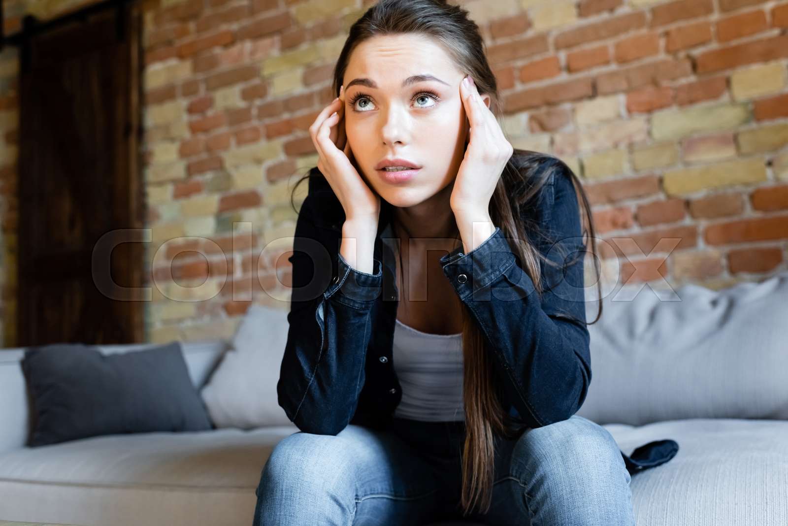 concentrated girl touching head while sitting on sofa | Stock image ...