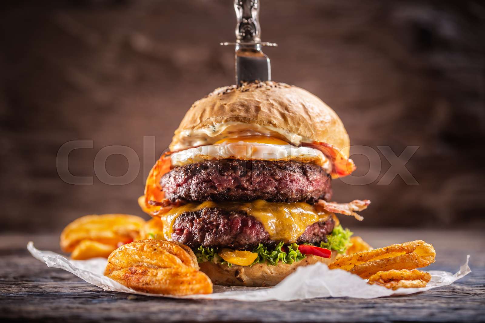 A knife-stabbed double-beef burger with melted cheese, fried egg and ...