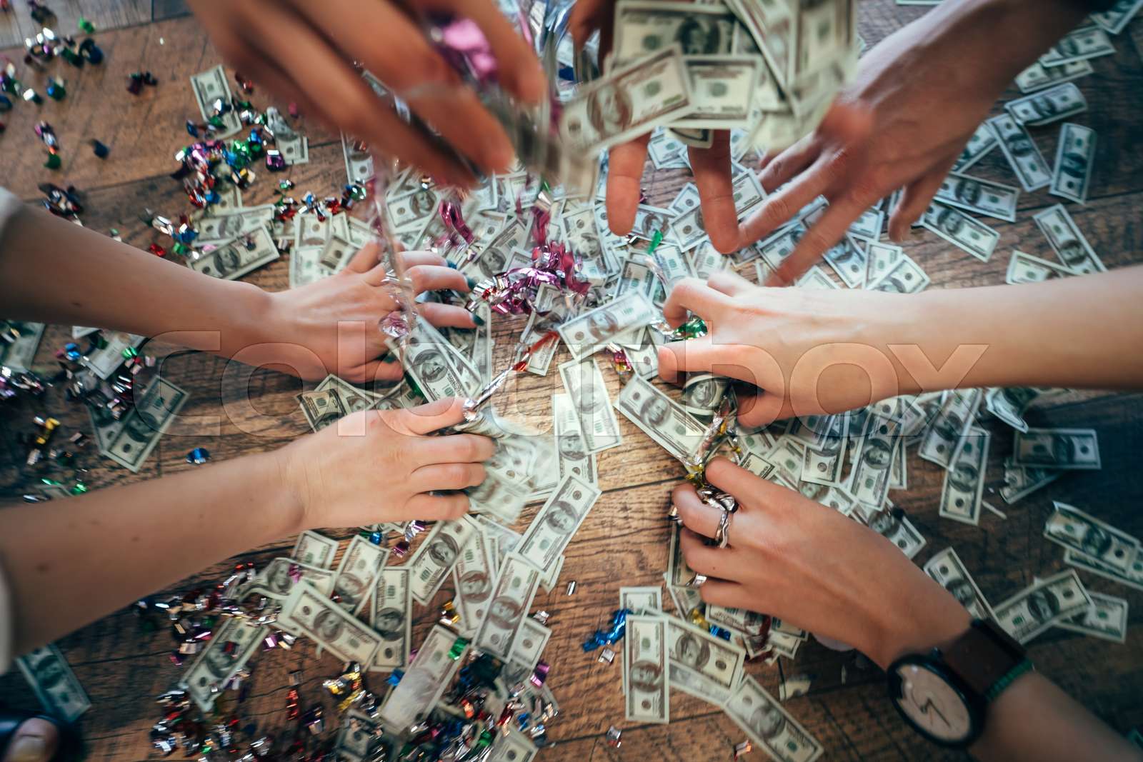 Several pairs of hands pick up dollar bills from the floor | Stock ...