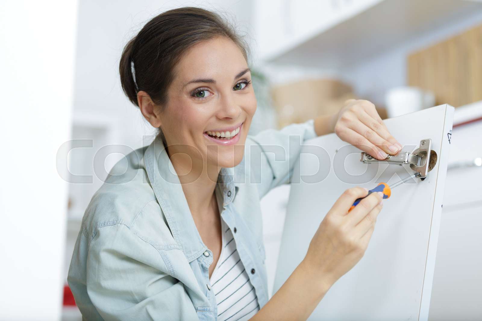 woman fixing a cabinet with a screwdriver | Stock image | Colourbox