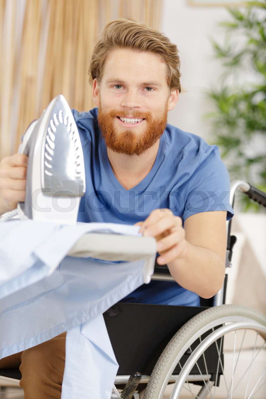 a young disable man ironing | Stock image | Colourbox