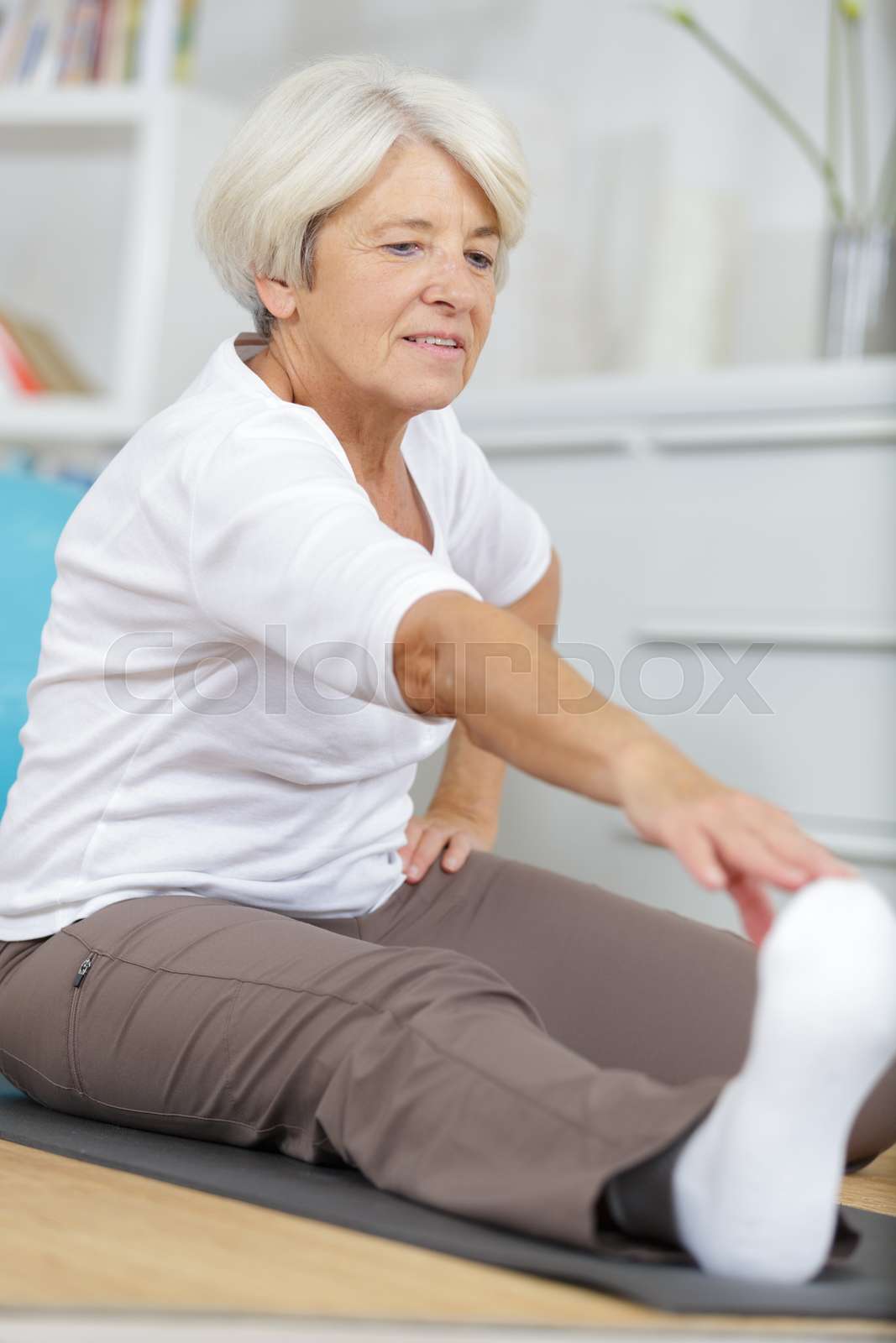 disabled mature woman performing stretching exercise | Stock image ...