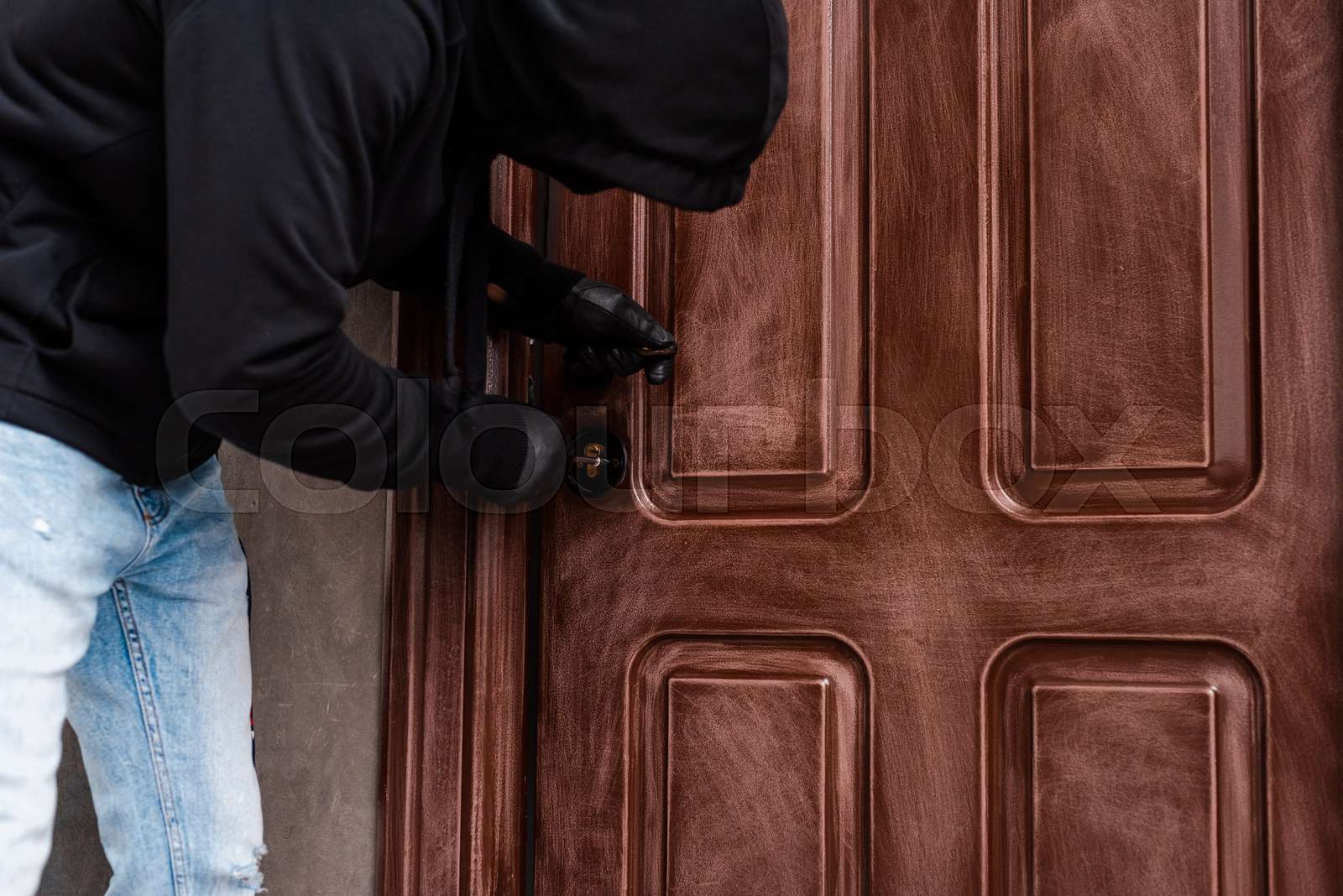 Side view of housebreaker using screwdriver while opening door lock ...