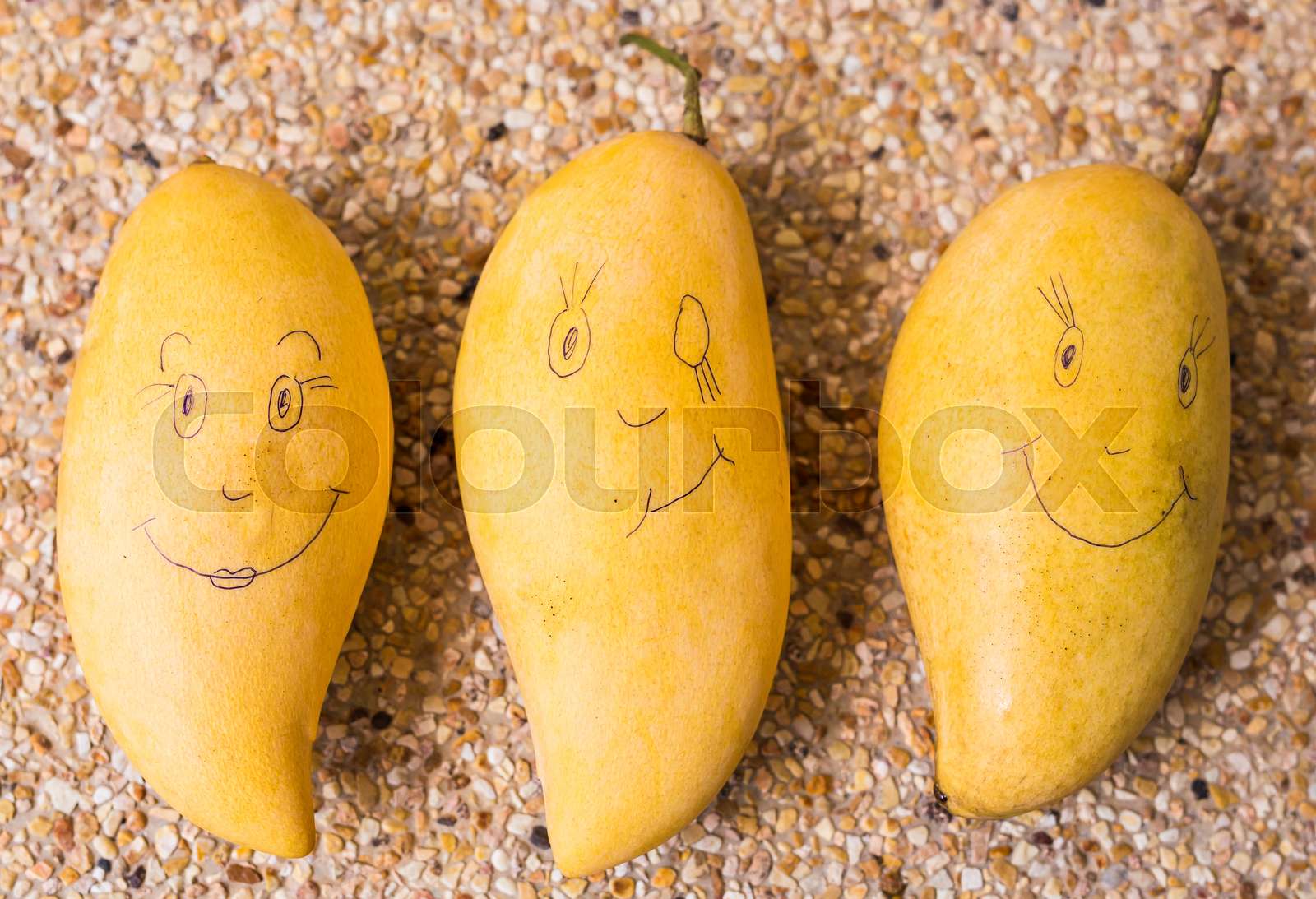 Drawn smiley face on a mango fruit. Fruits, diet, healthy food concept ...