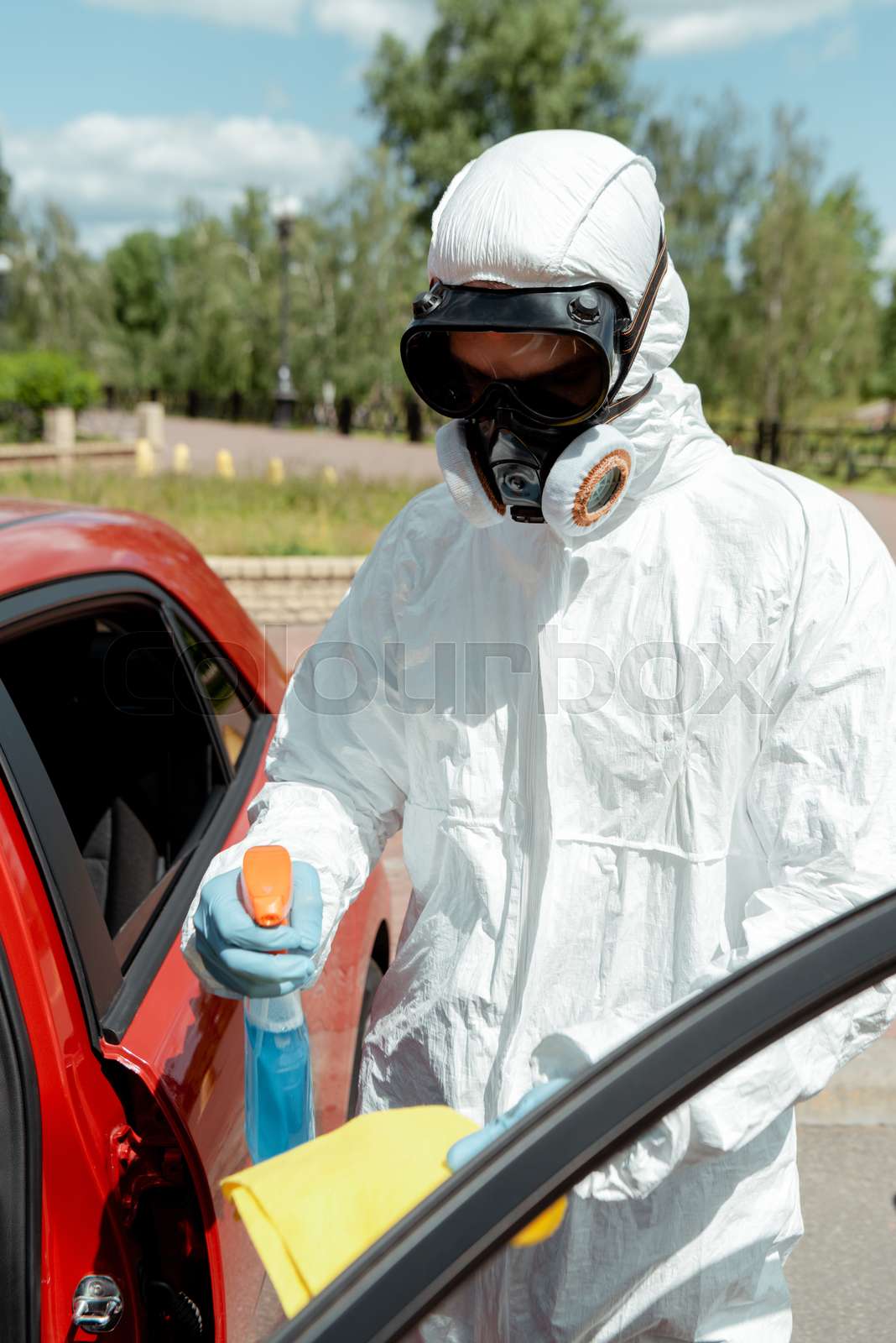 cleaner in hazmat suit cleaning car with antiseptic spray and rag ...