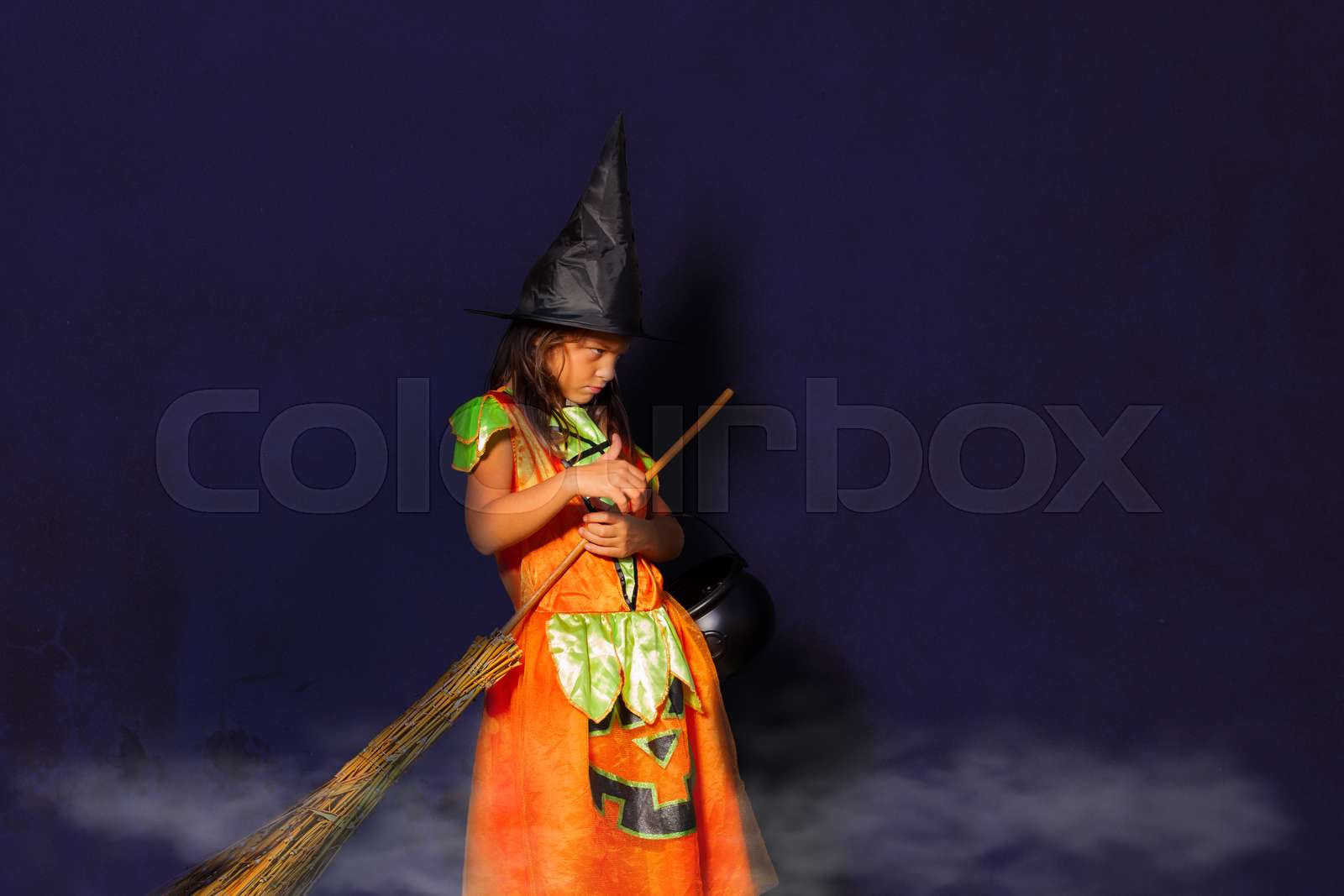 Grumpy girl in Halloween witch costume with broom | Stock image | Colourbox