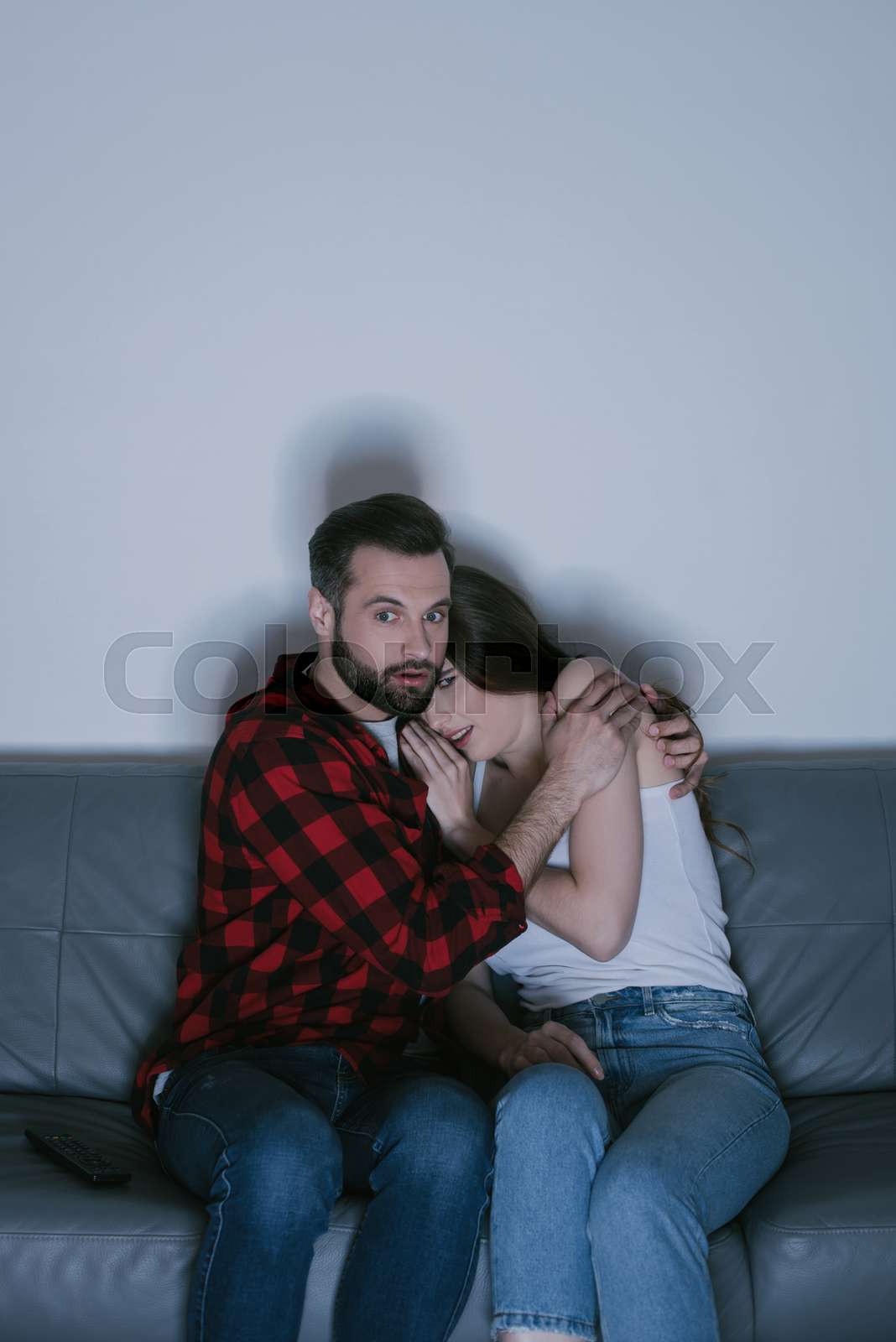 scared man hugging frightened girl while watching movie together at ...